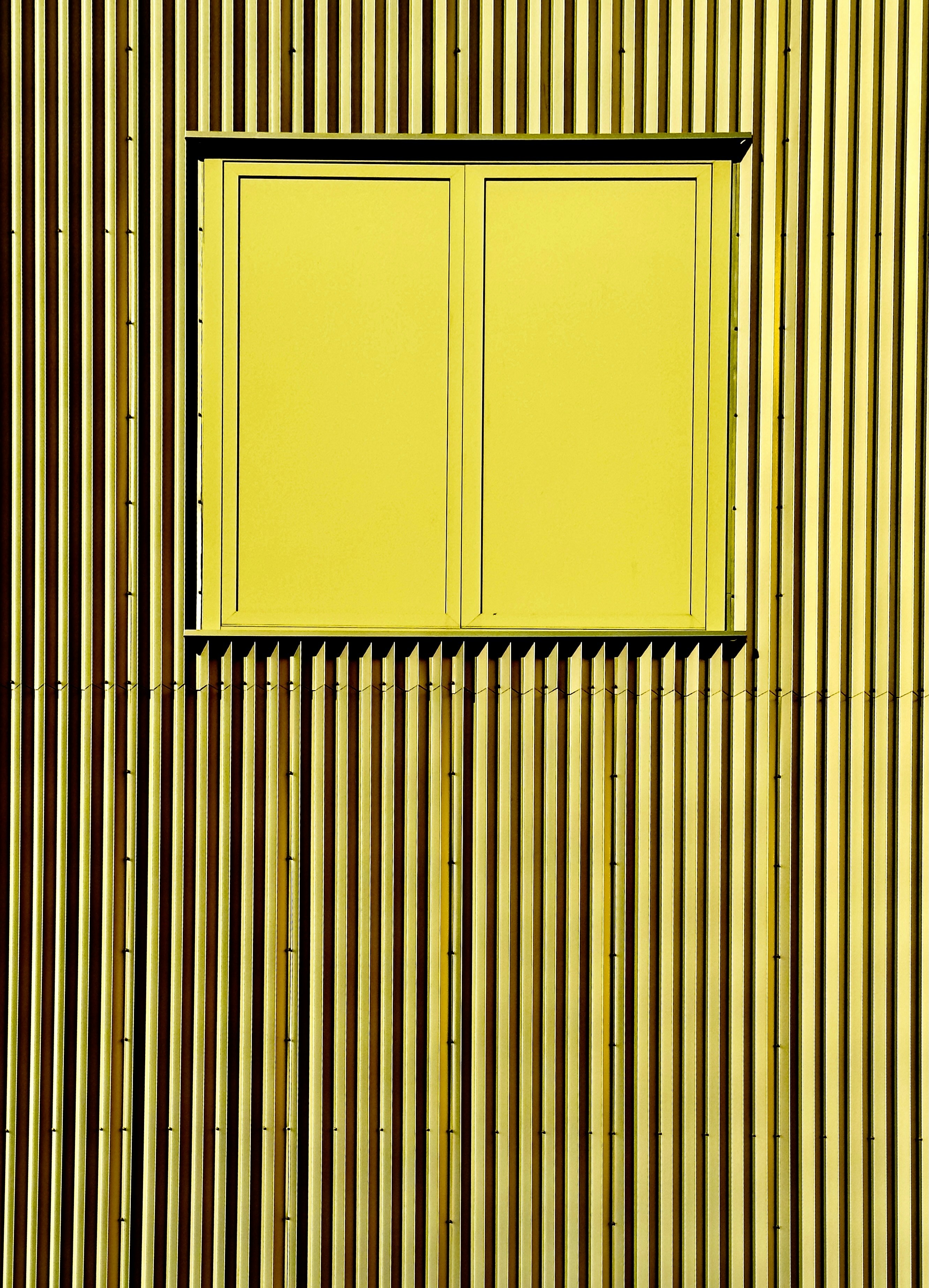Sunlit Yellow Facade: A Centered Window Framed by Vertical Rhythm