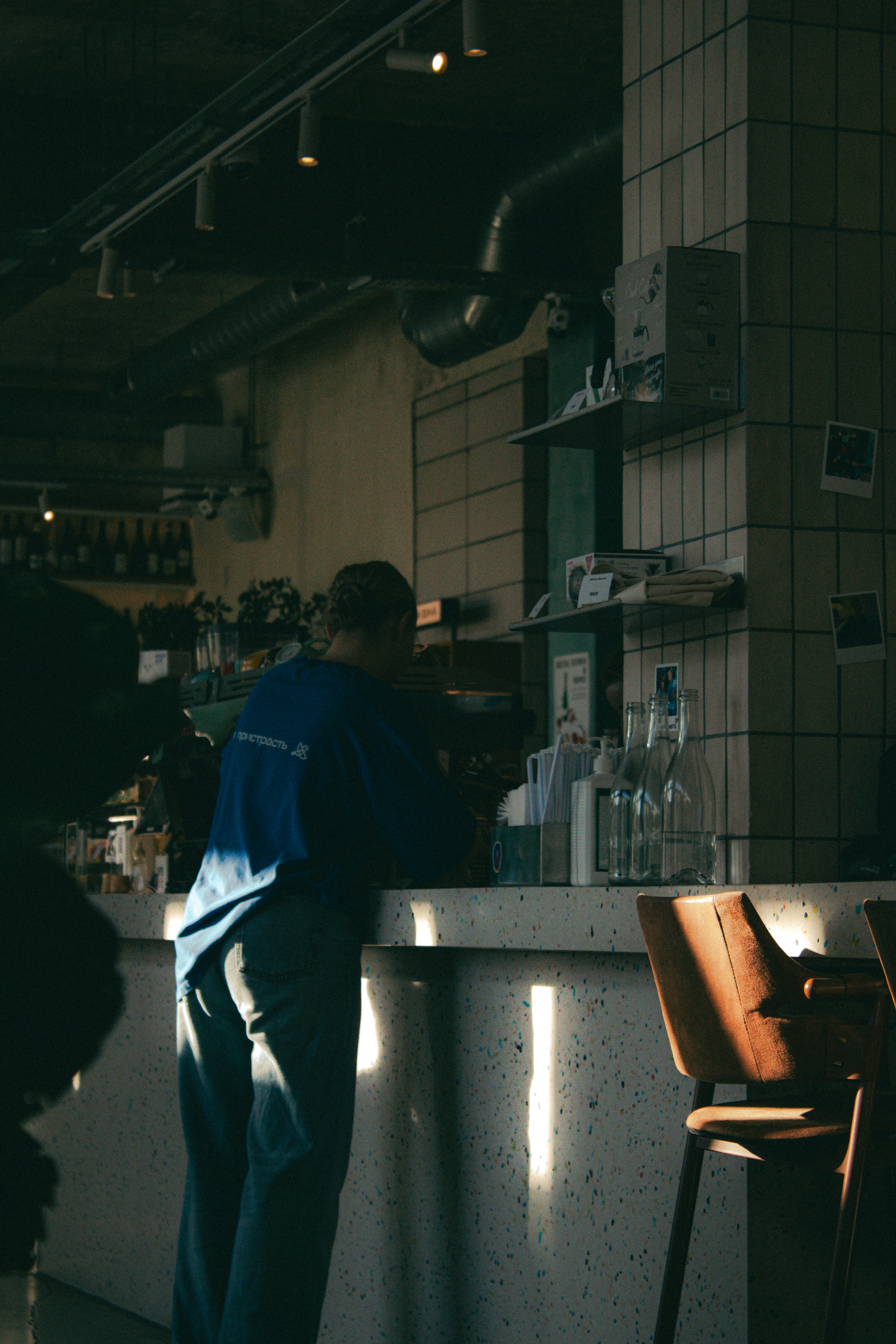 Barista preparing drinks at a minimalist café, sunlight casting soft shadows on the counter.