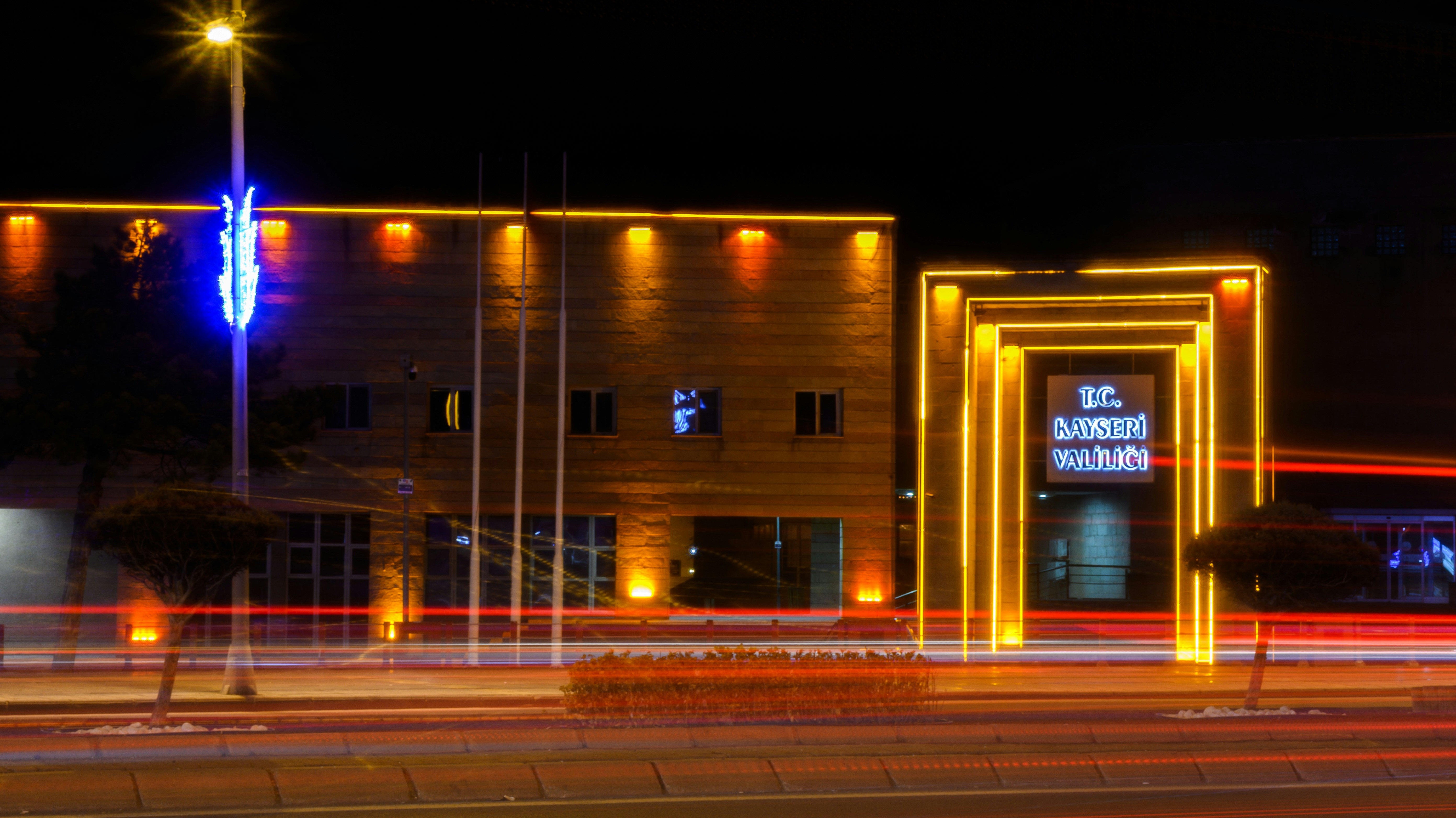 Illuminated building facade with vibrant light trails from passing vehicles at night.