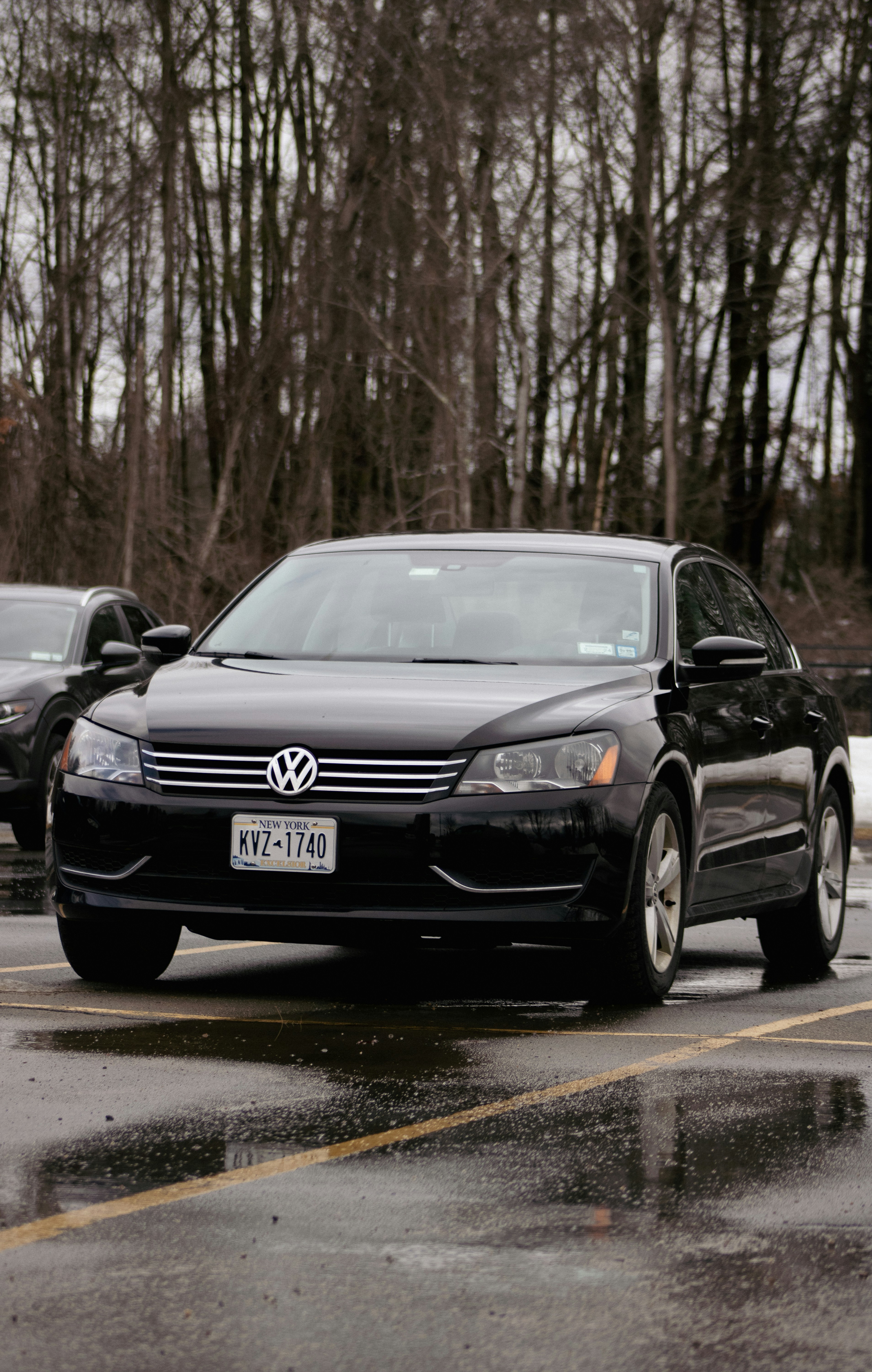 Front-Grille Focus: Black VW Sedan in a Rain-Slick Parking Lot
