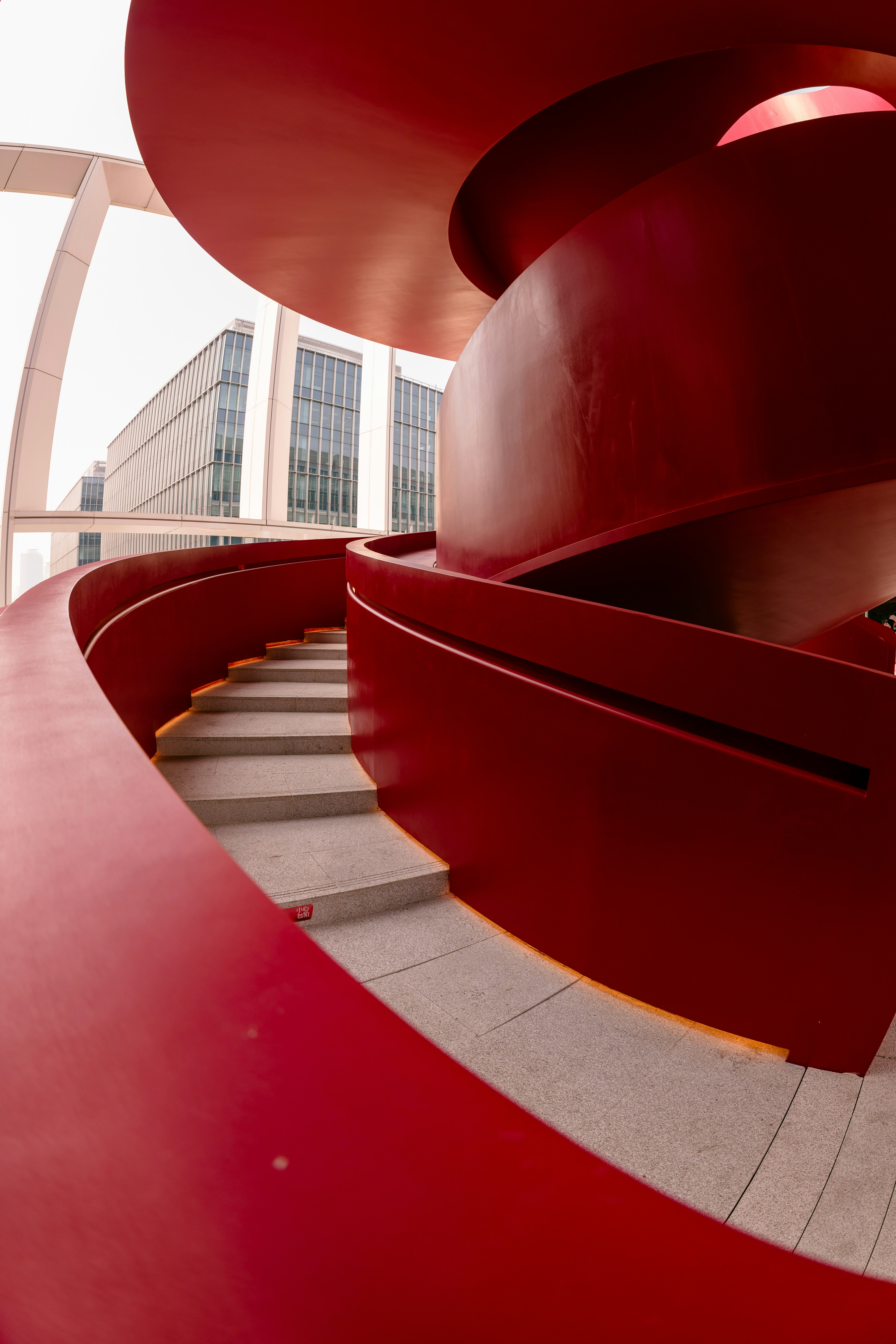 Crimson Helix Over Urban Glass: The Red Spiral Staircase