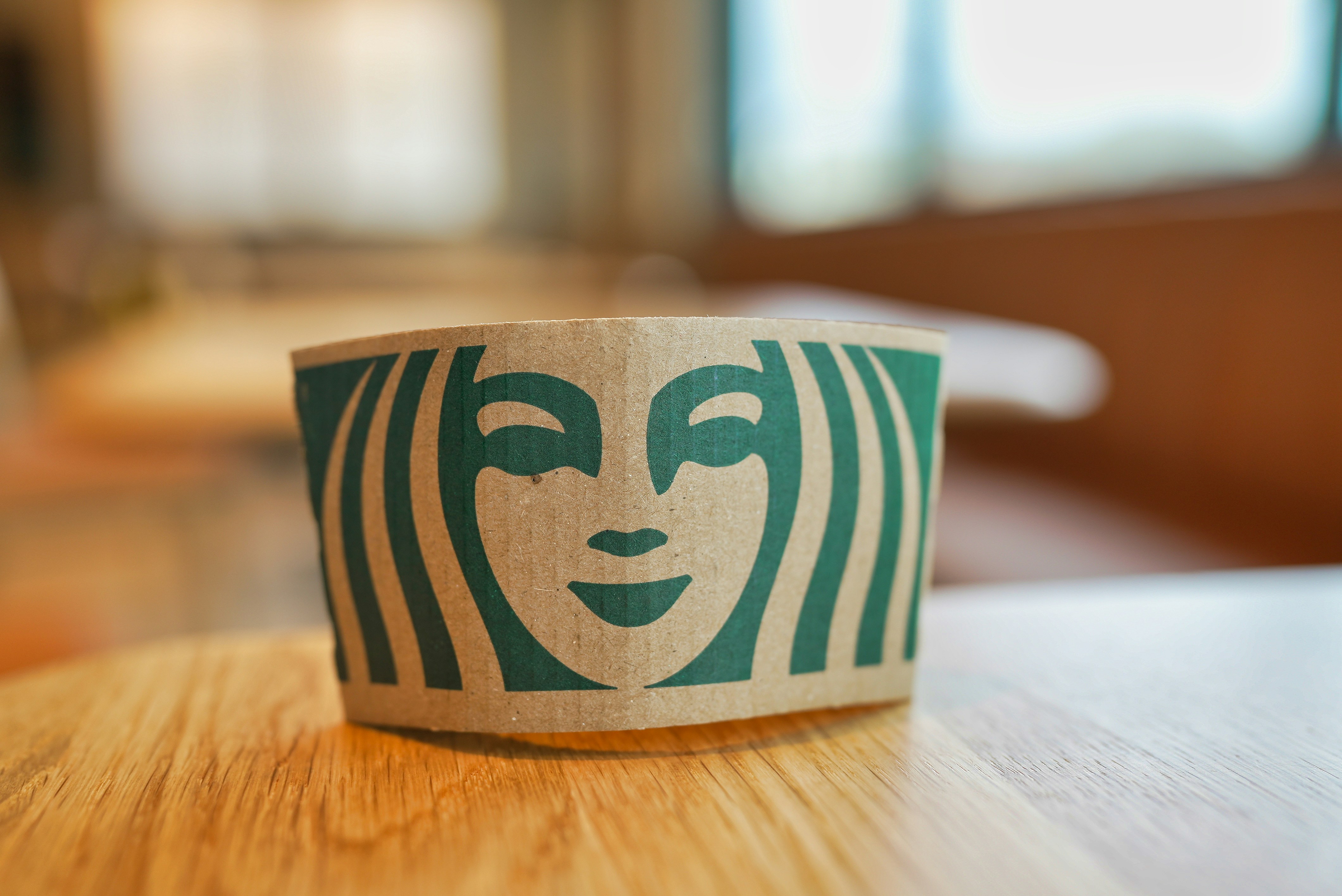 Bold Starbucks cup on a warm wooden surface with a soft café background.