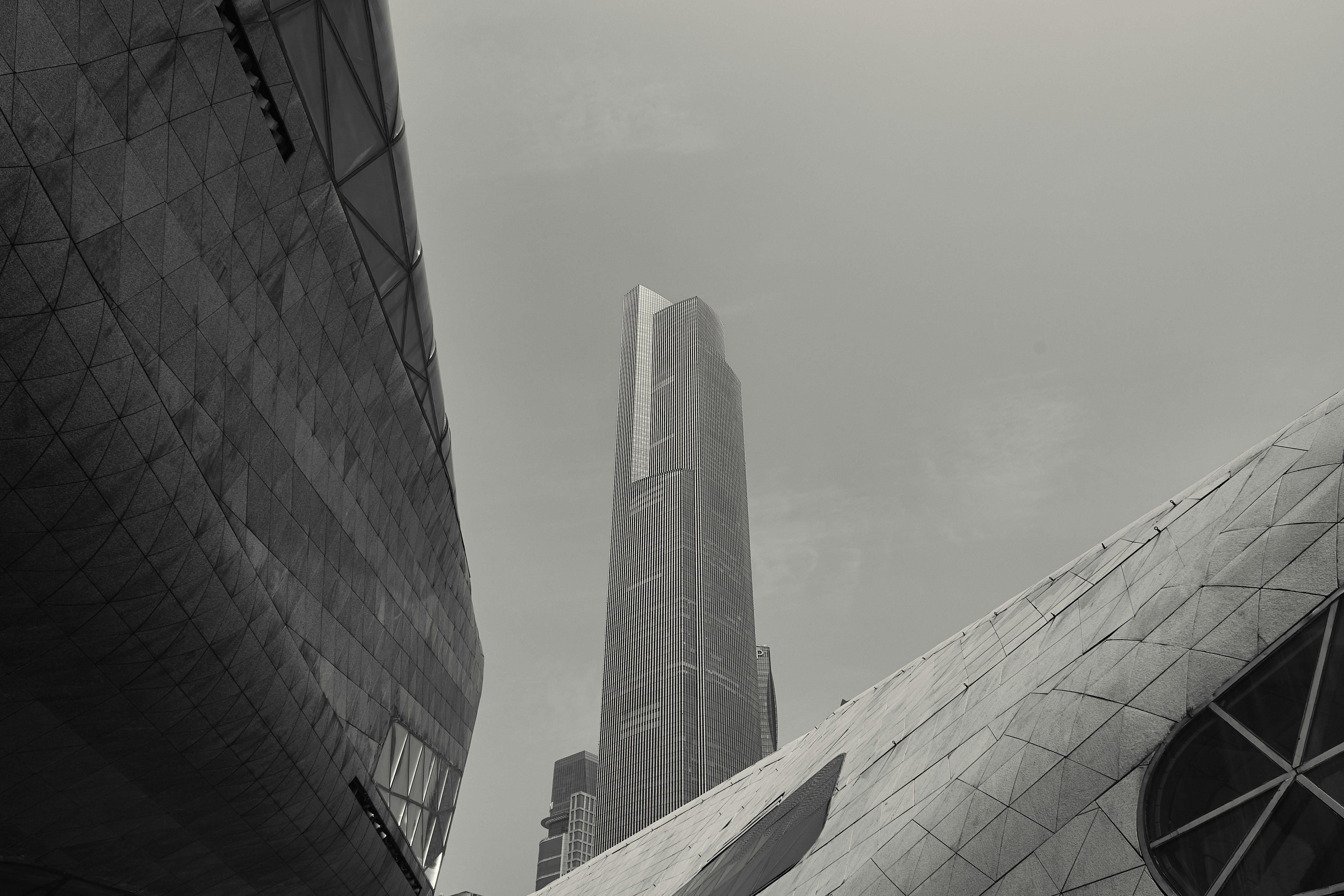 Monochrome architectural view with towering skyscraper framed by angular modern buildings.