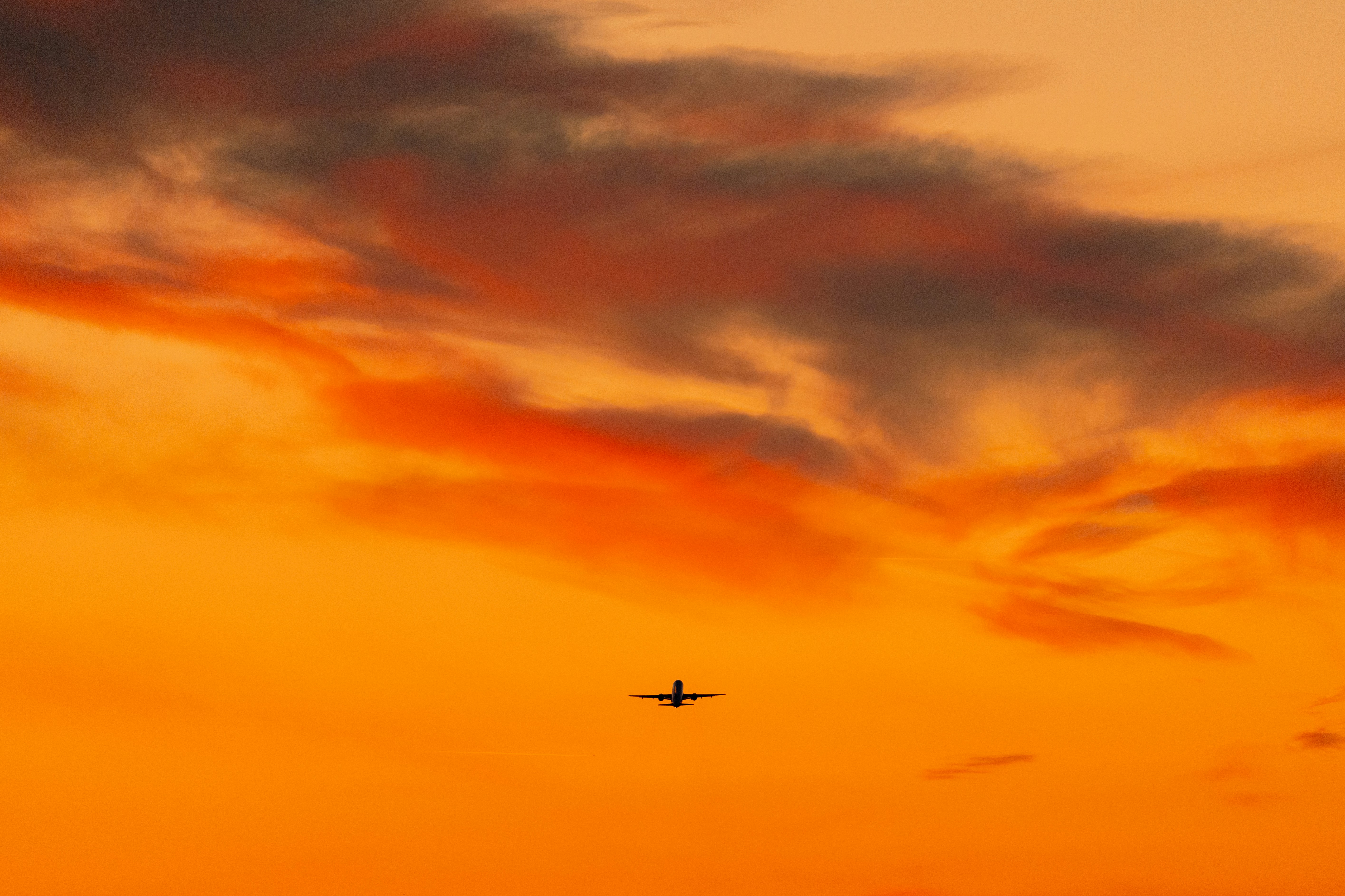 Airplane flies through a stunning sunset.