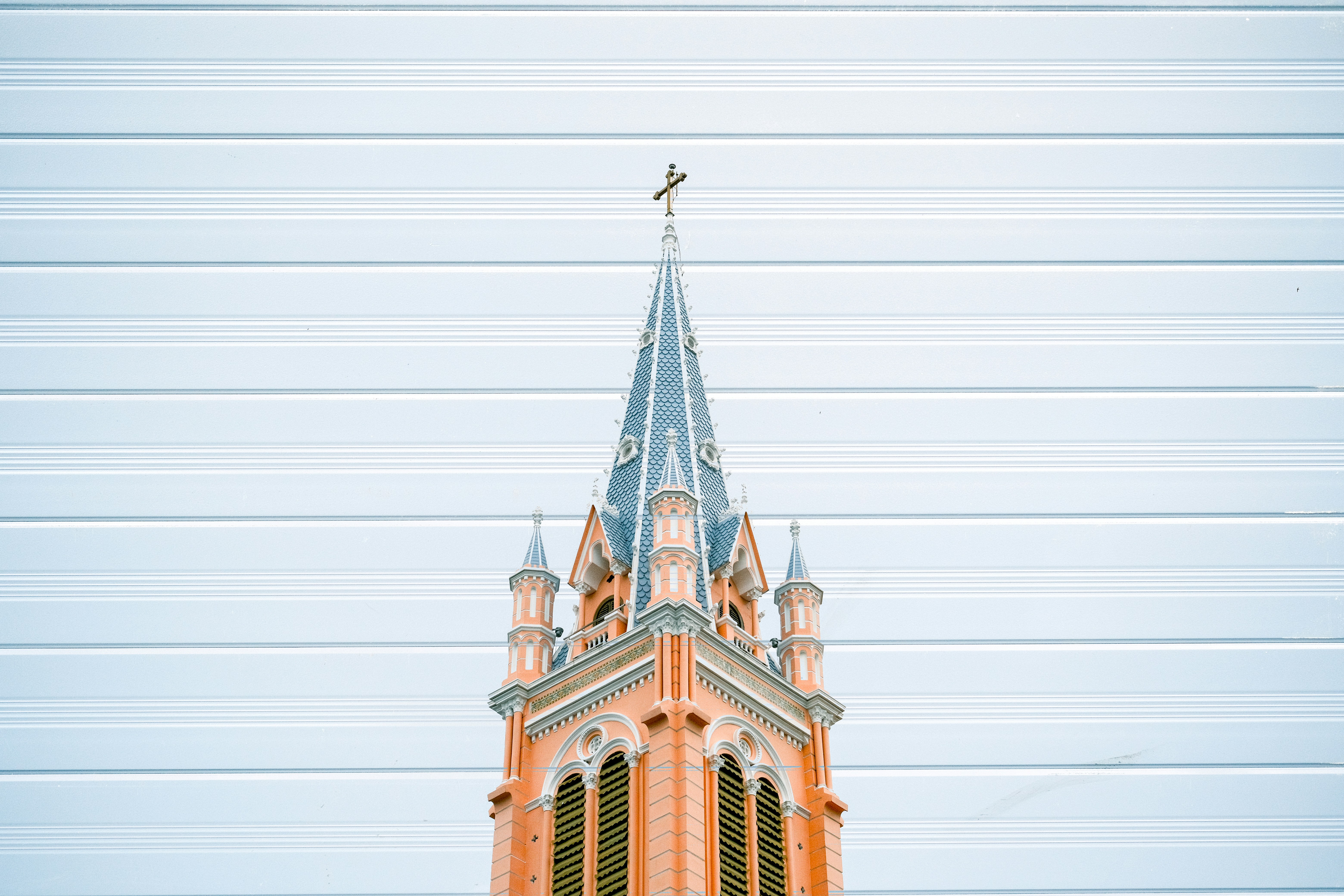 Pastel Spire Rising Over a Striped Blue Facade