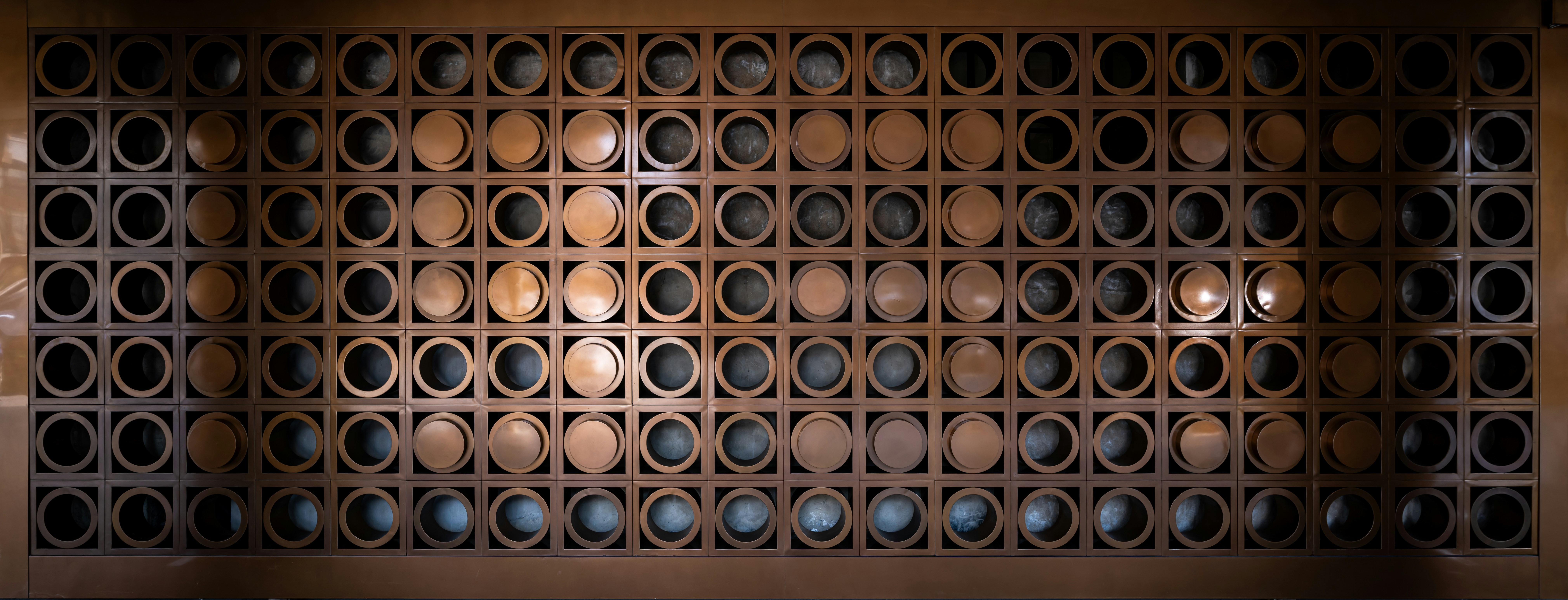 Intricate pattern of circular cutouts in a metallic architectural structure, illuminated with warm lighting.