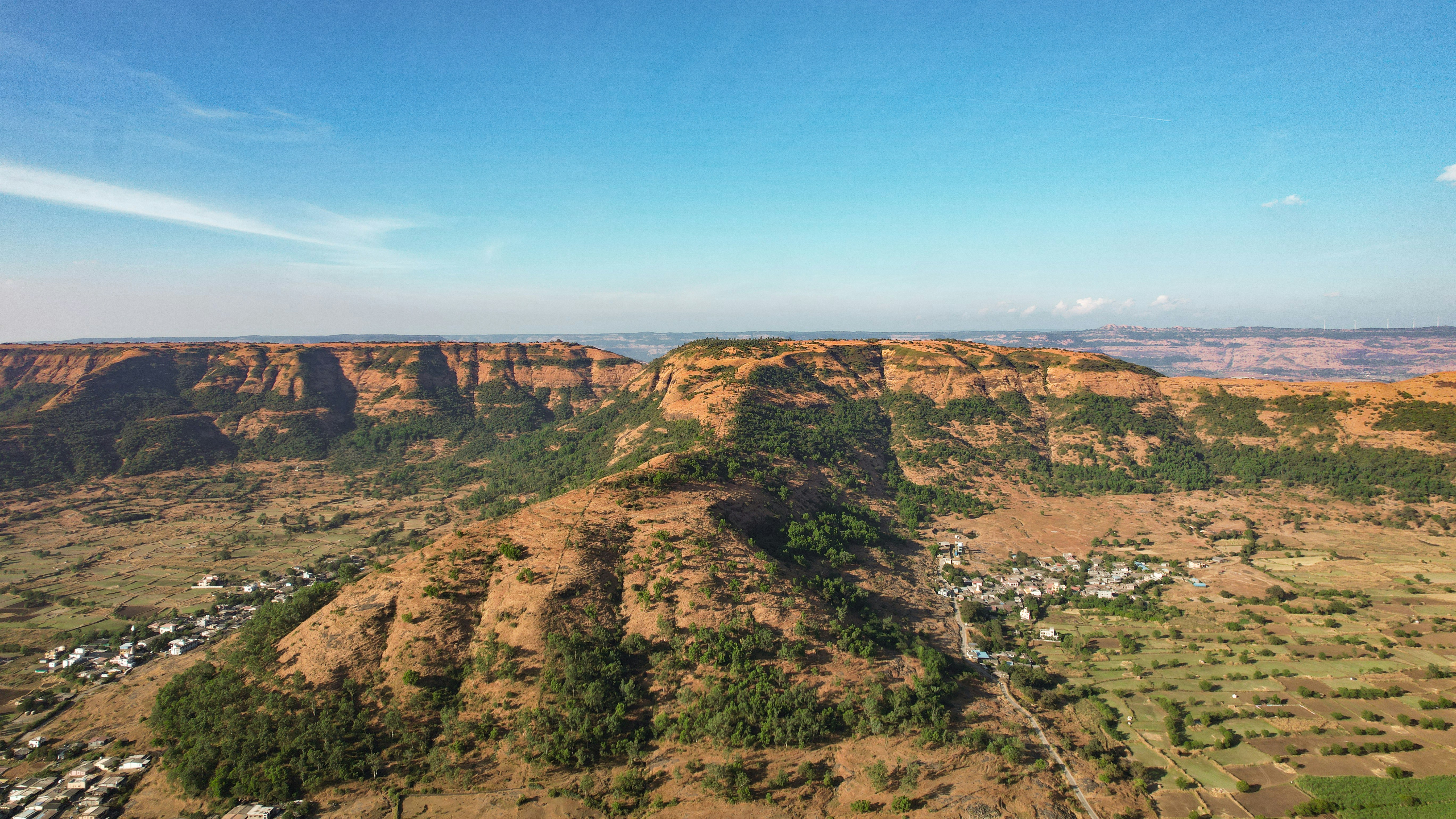 Expansive green valleys and rugged cliffs under a clear blue sky.