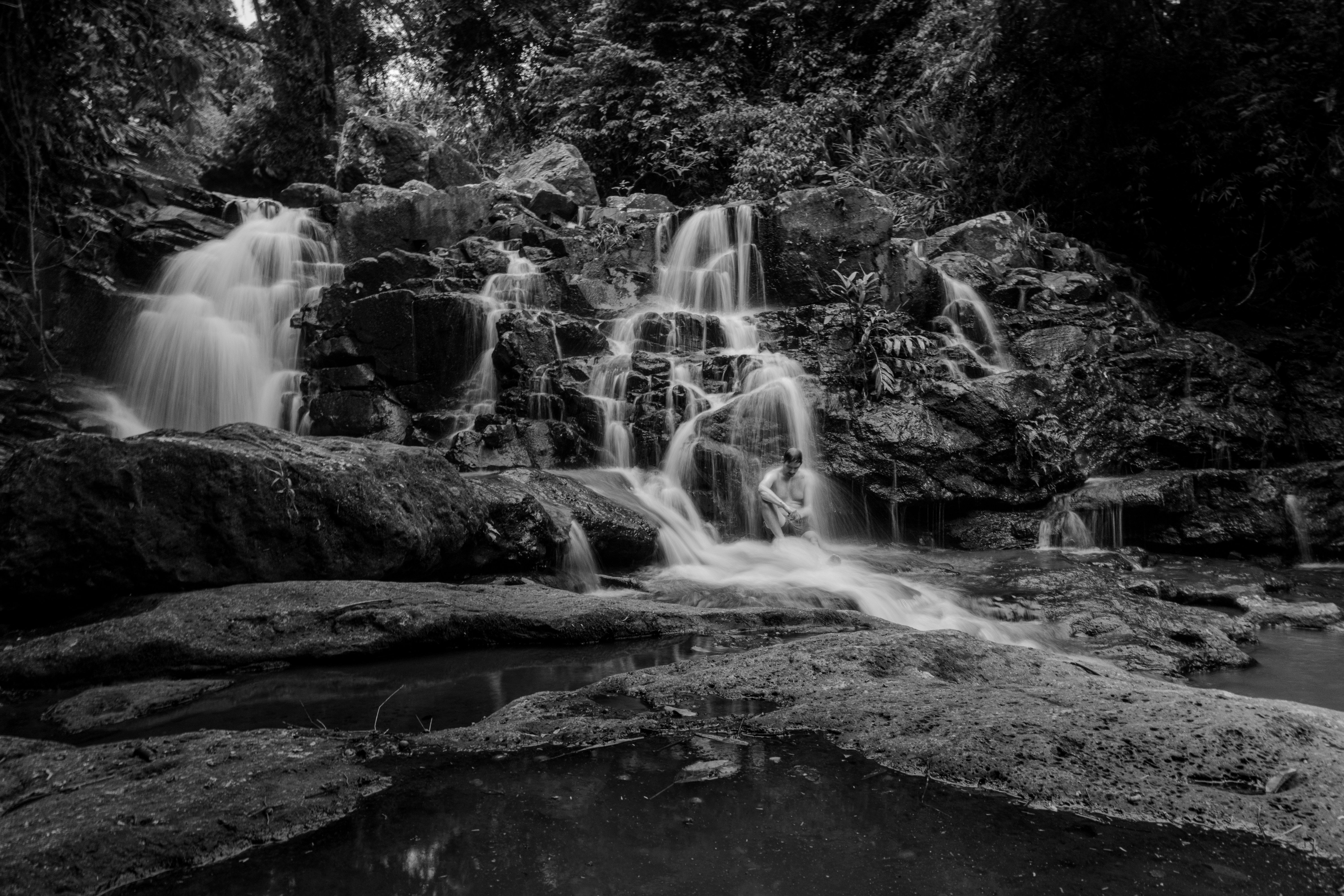 Black and white waterfall cascading over rocks surrounded by lush foliage.