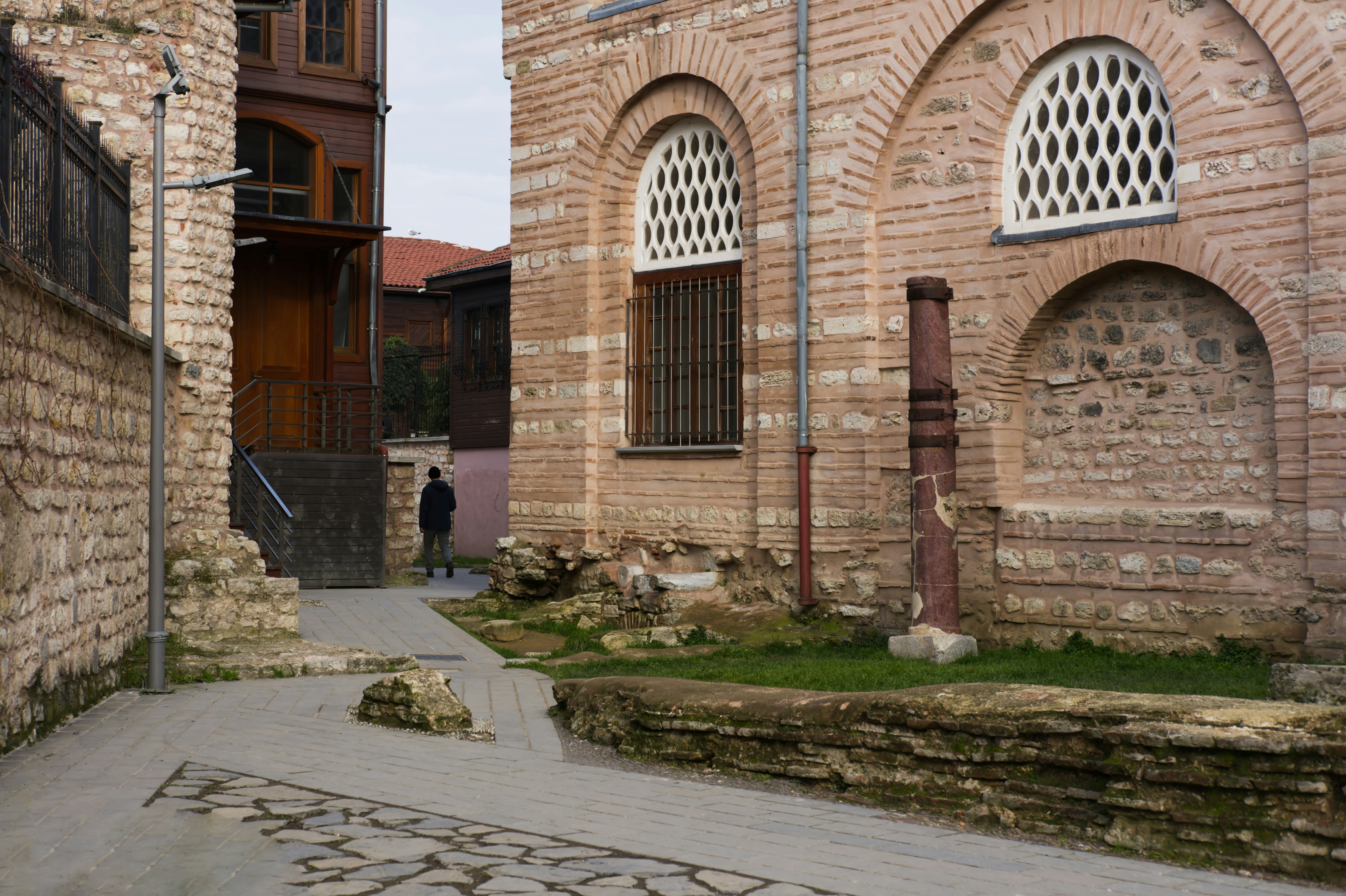 Distant Figure Framed by Arched Brick Corridor