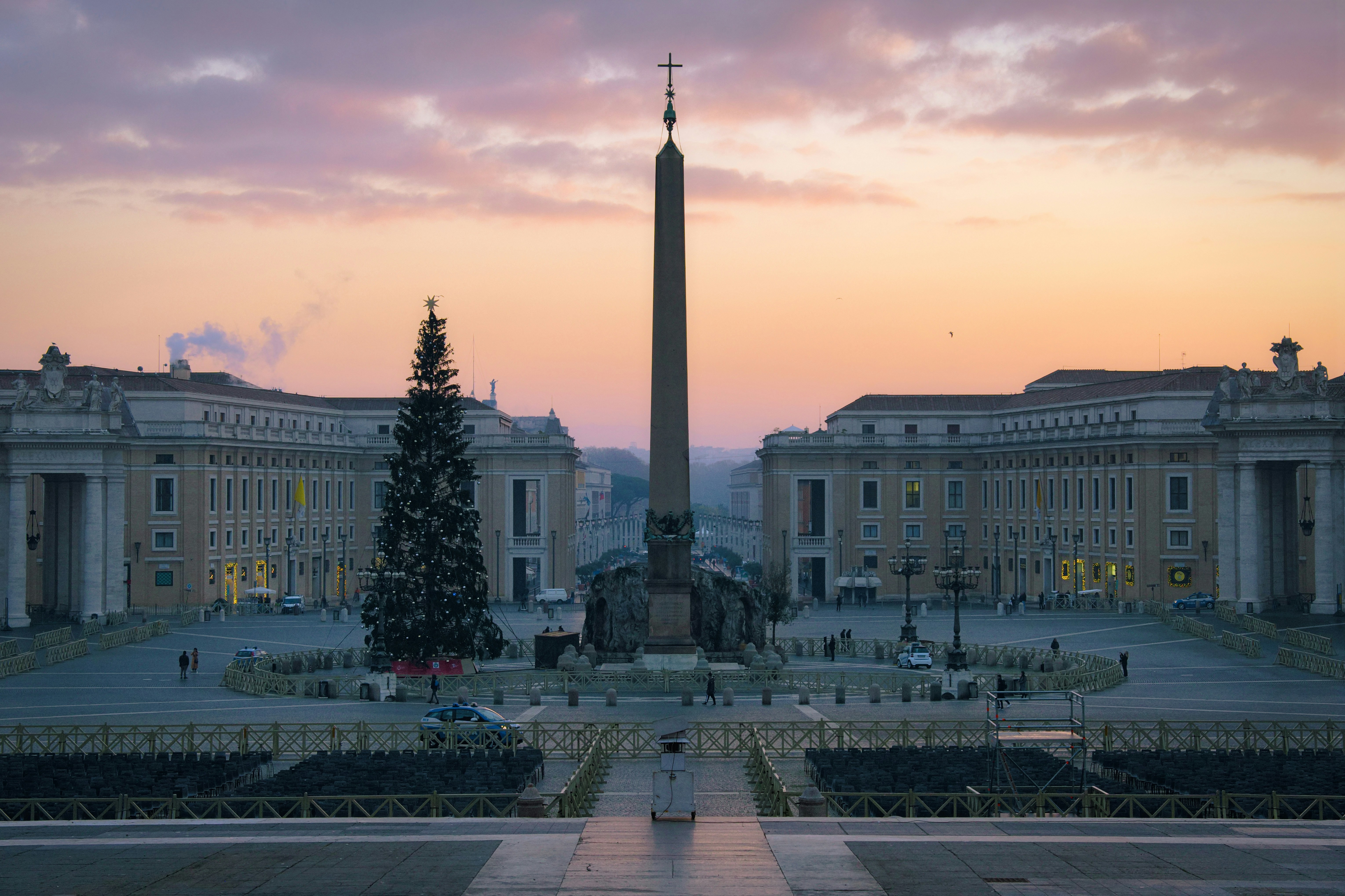 St. Peter's Square at dawn with a tall Christmas tree beside the obelisk.