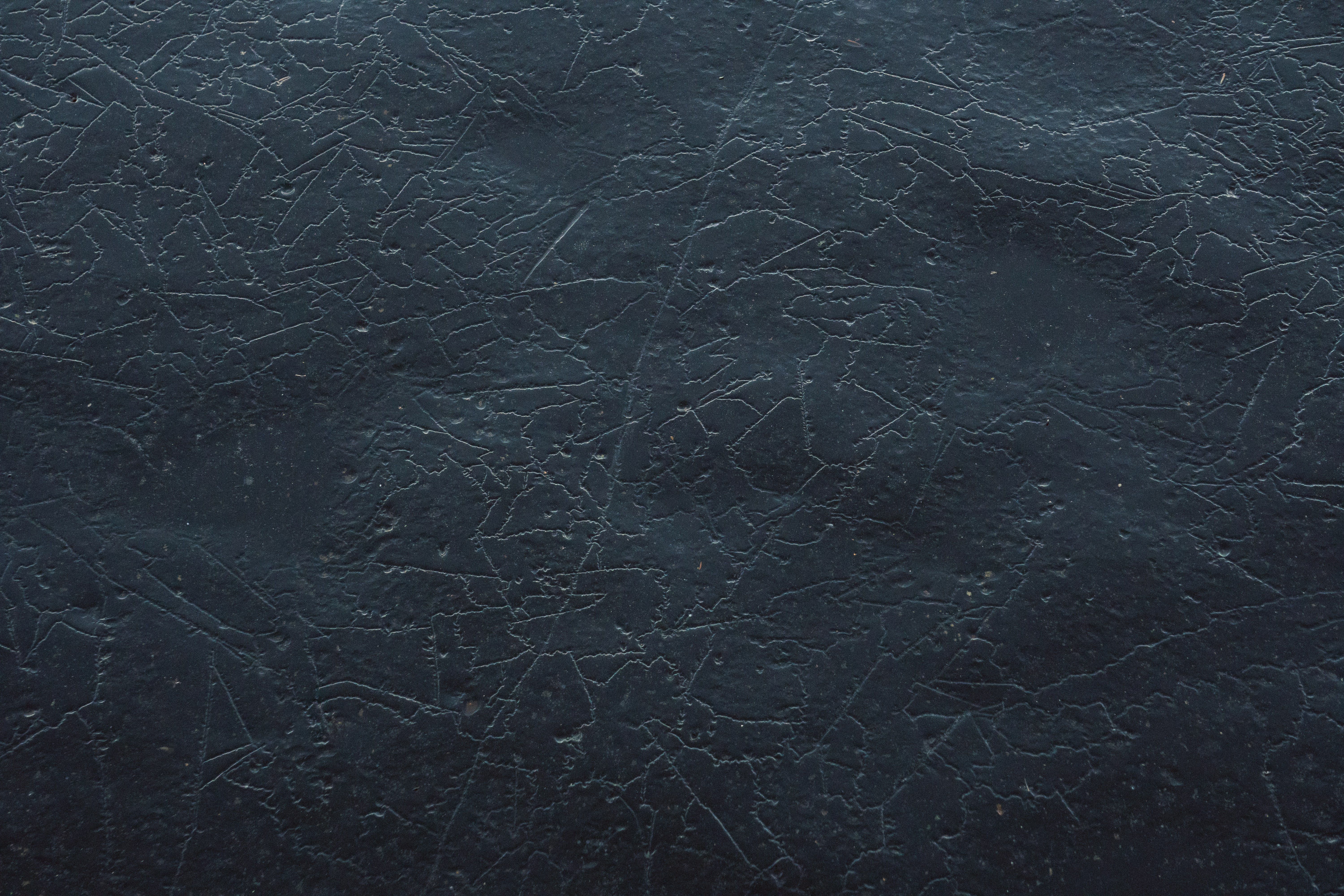 Network of intricate cracks on a dark icy surface.