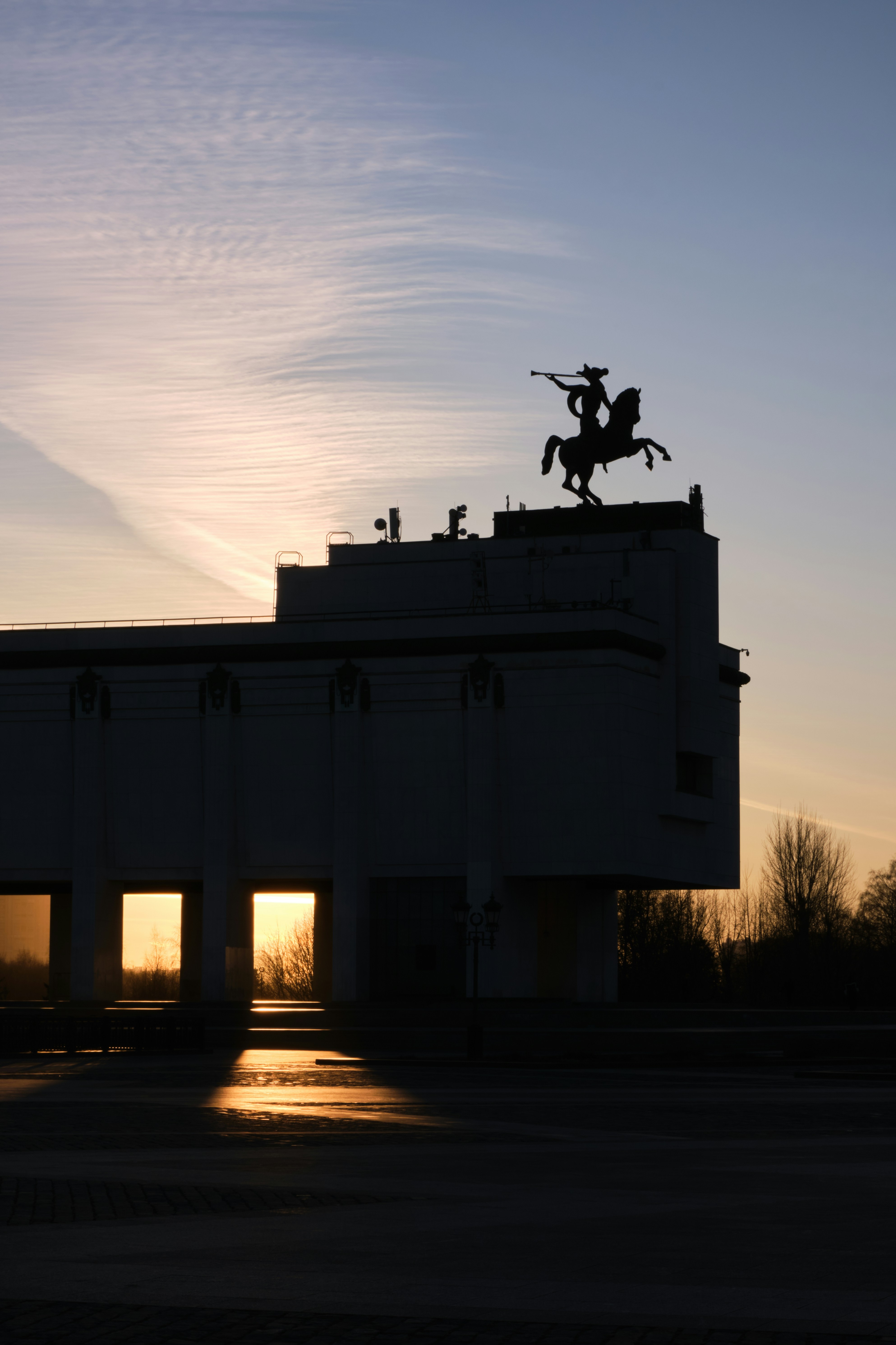 A striking silhouette of a monument featuring a mounted figure against a twilight sky, with warm light visible through the structure's openings.