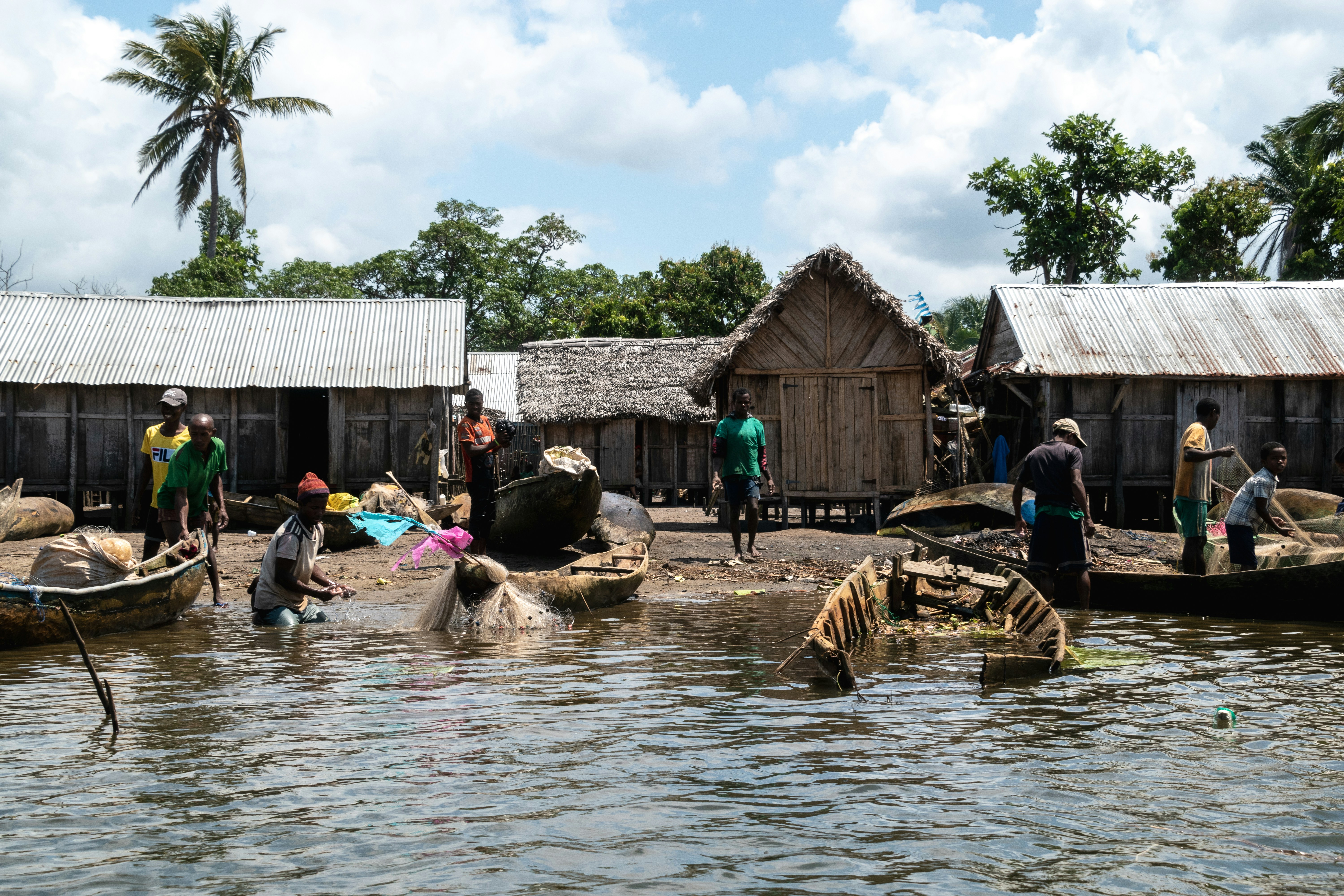 People stand outside huts on a watery landscape. photo – Free Human ...