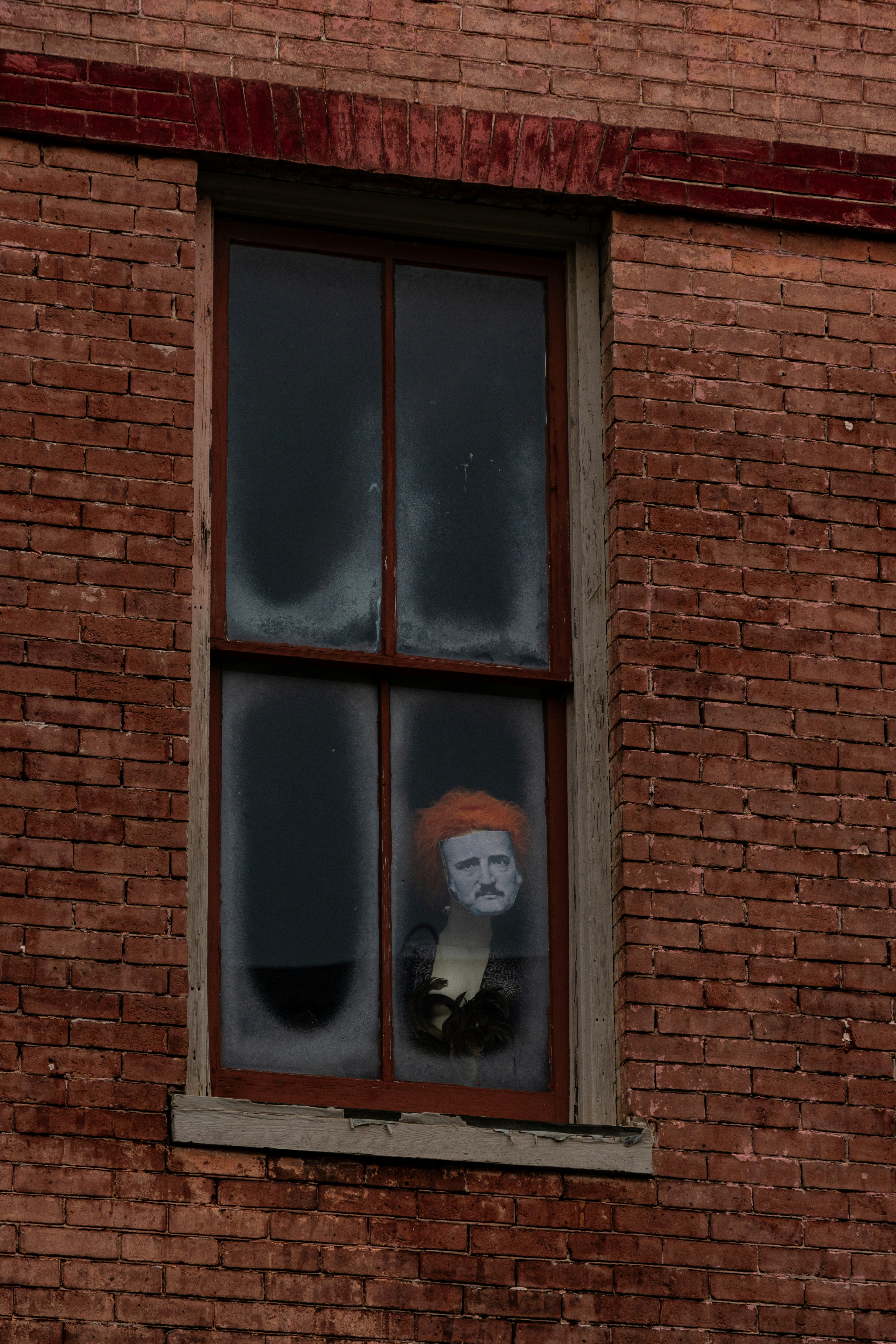 A bust statue in a window of a brick building. photo – Free Man Image ...