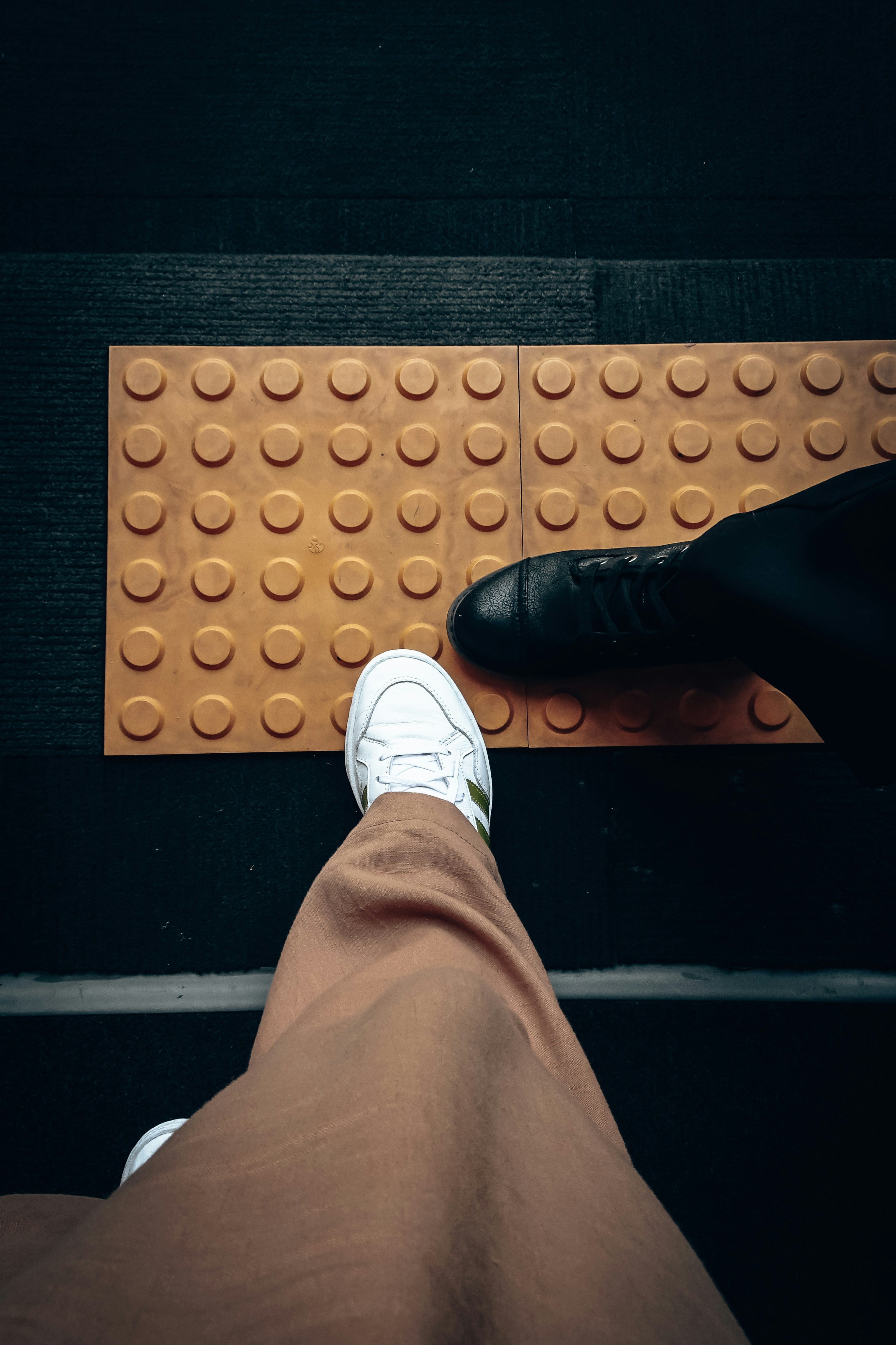 Two contrasting shoes on a textured orange mat, highlighting the intersection of styles and perspectives.