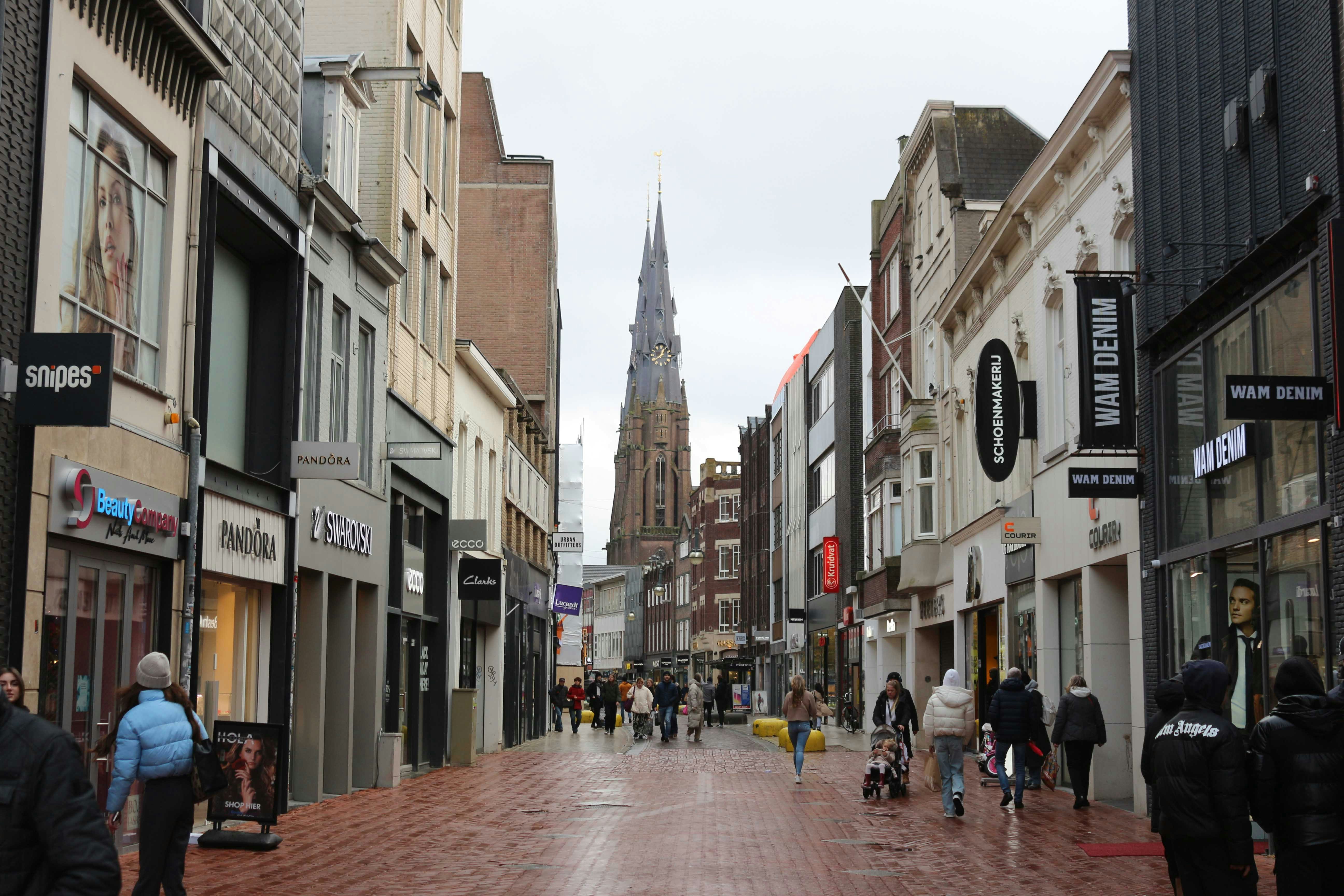 A busy street leads to a spired church. photo – Free City Image on Unsplash