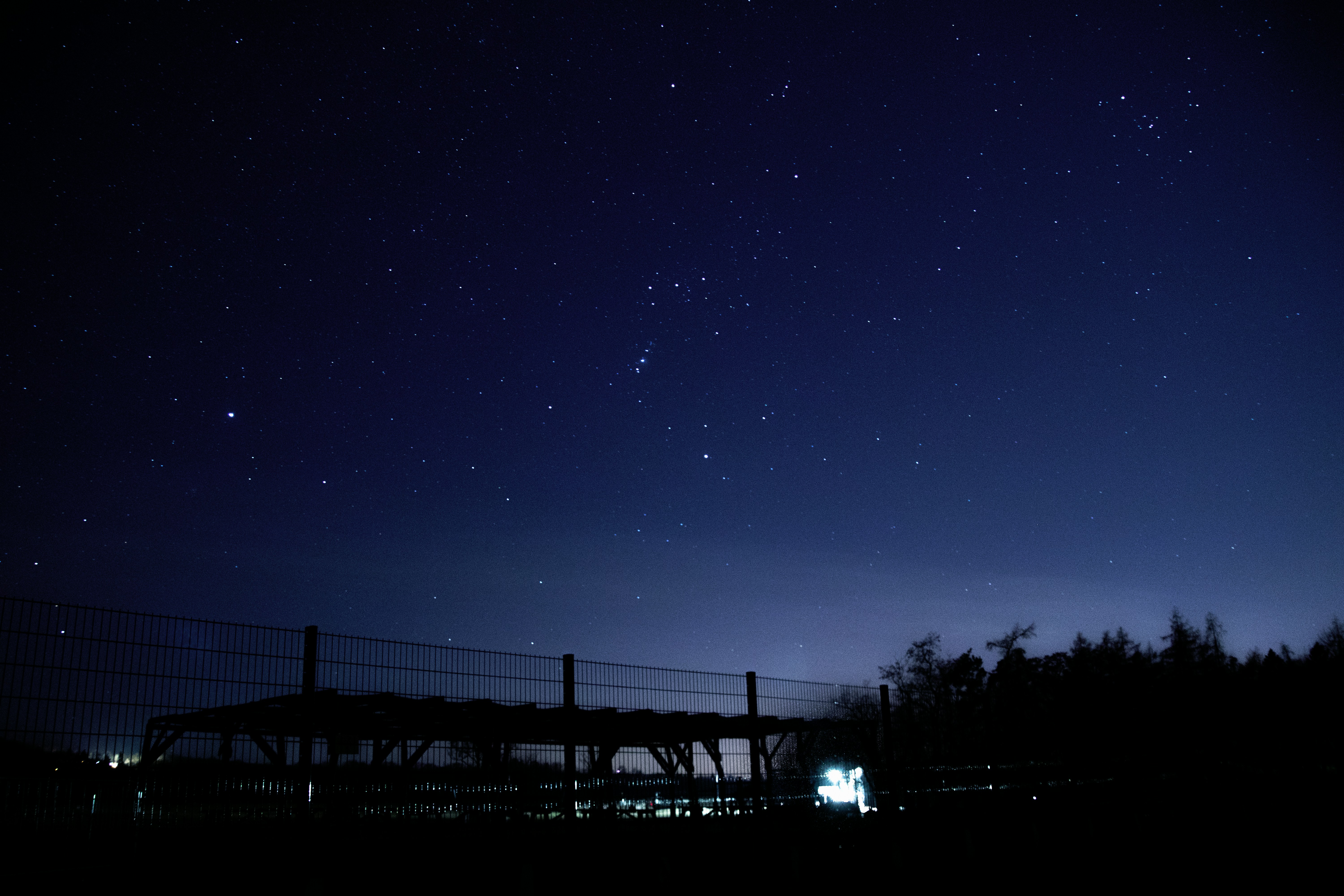 Night sky with stars and silhouetted structures.