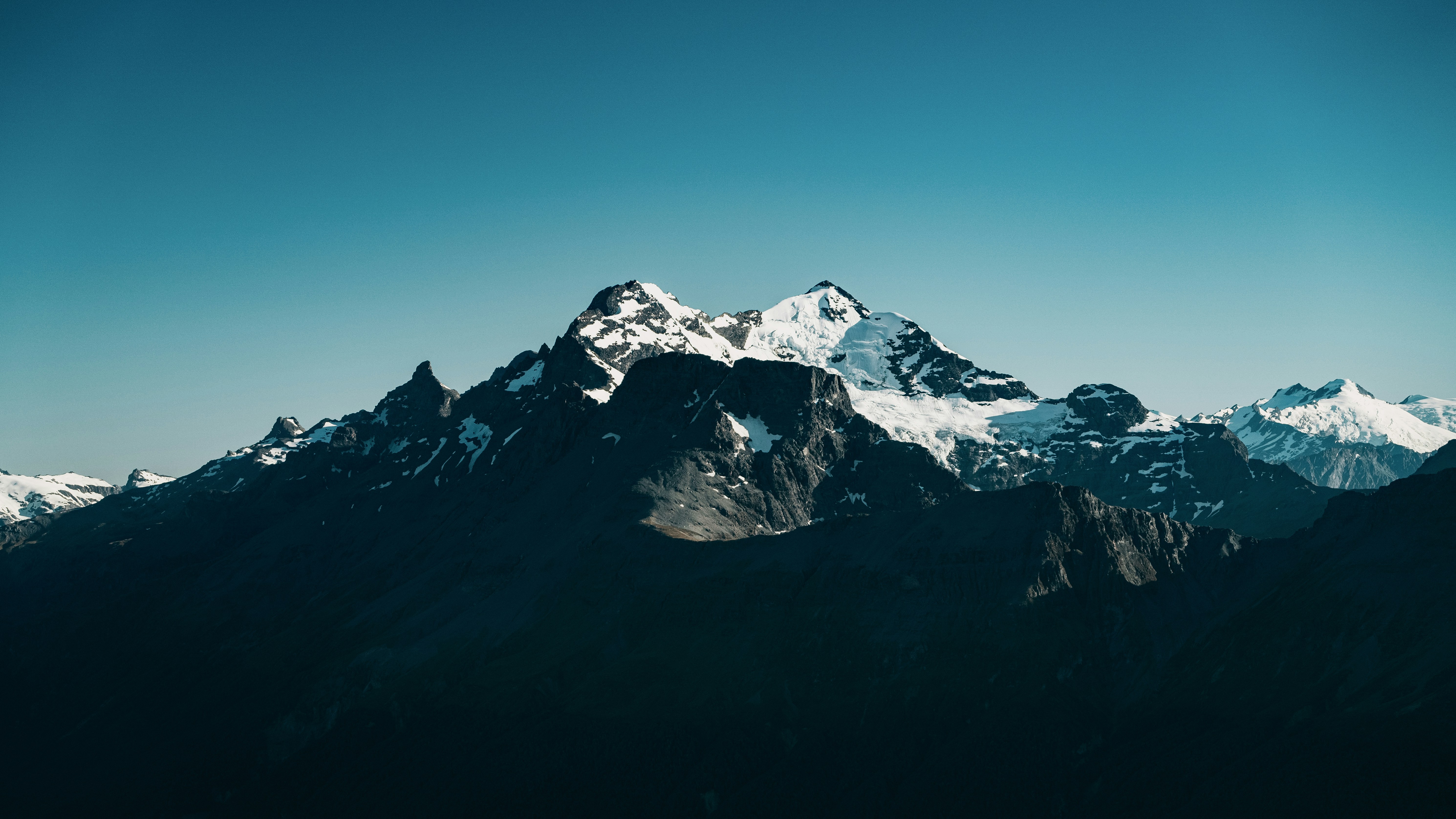 Snow-capped mountains stand tall against a clear blue sky. photo – Free ...