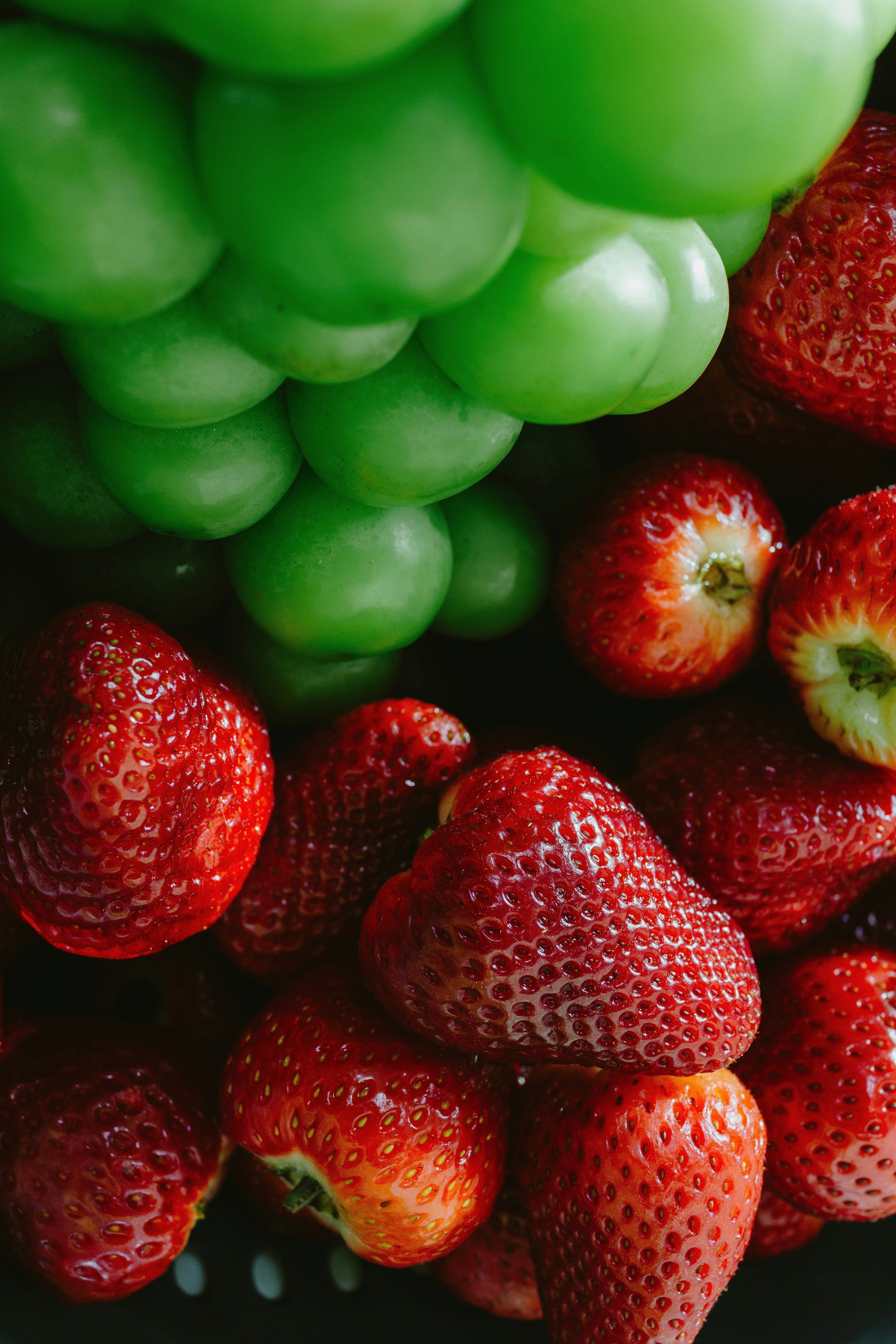 Crimson Strawberries Nestled Among Emerald Grapes: A Macro Harvest Portrait