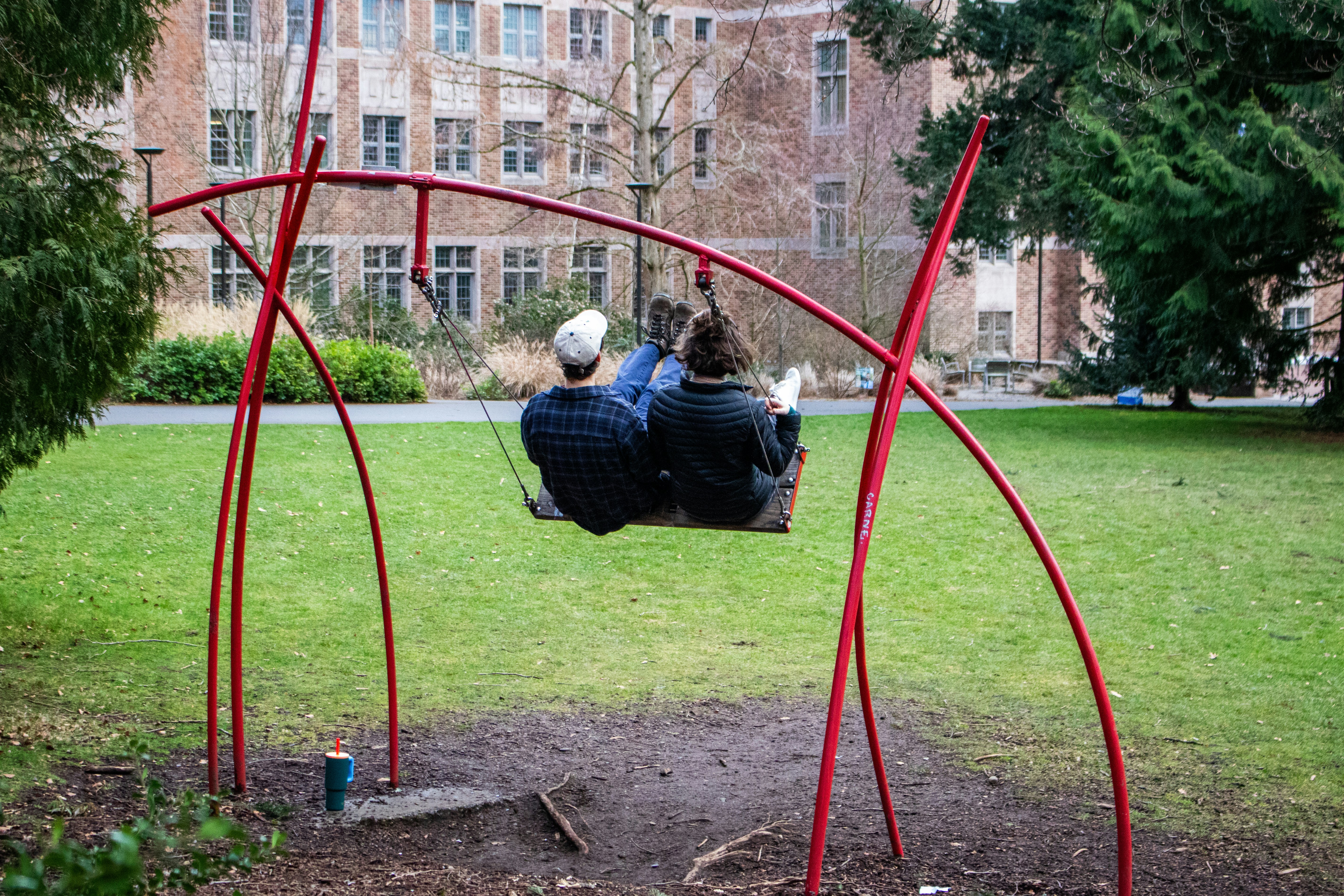 Two people swing on a unique red swing set. photo – Free Woman Image on ...