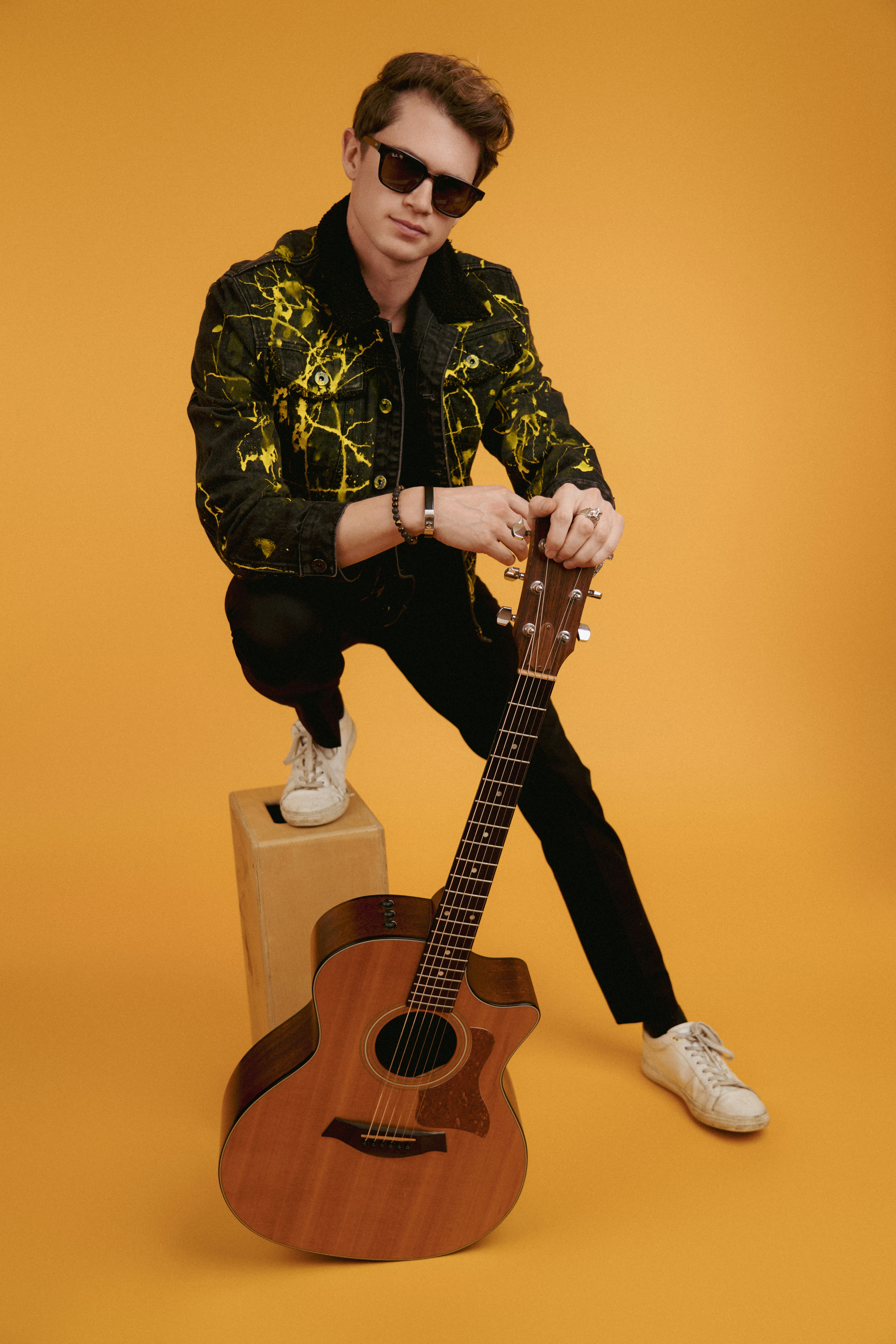 Amber Backdrop, Quiet Confidence: A Guitarist's Studio Pose