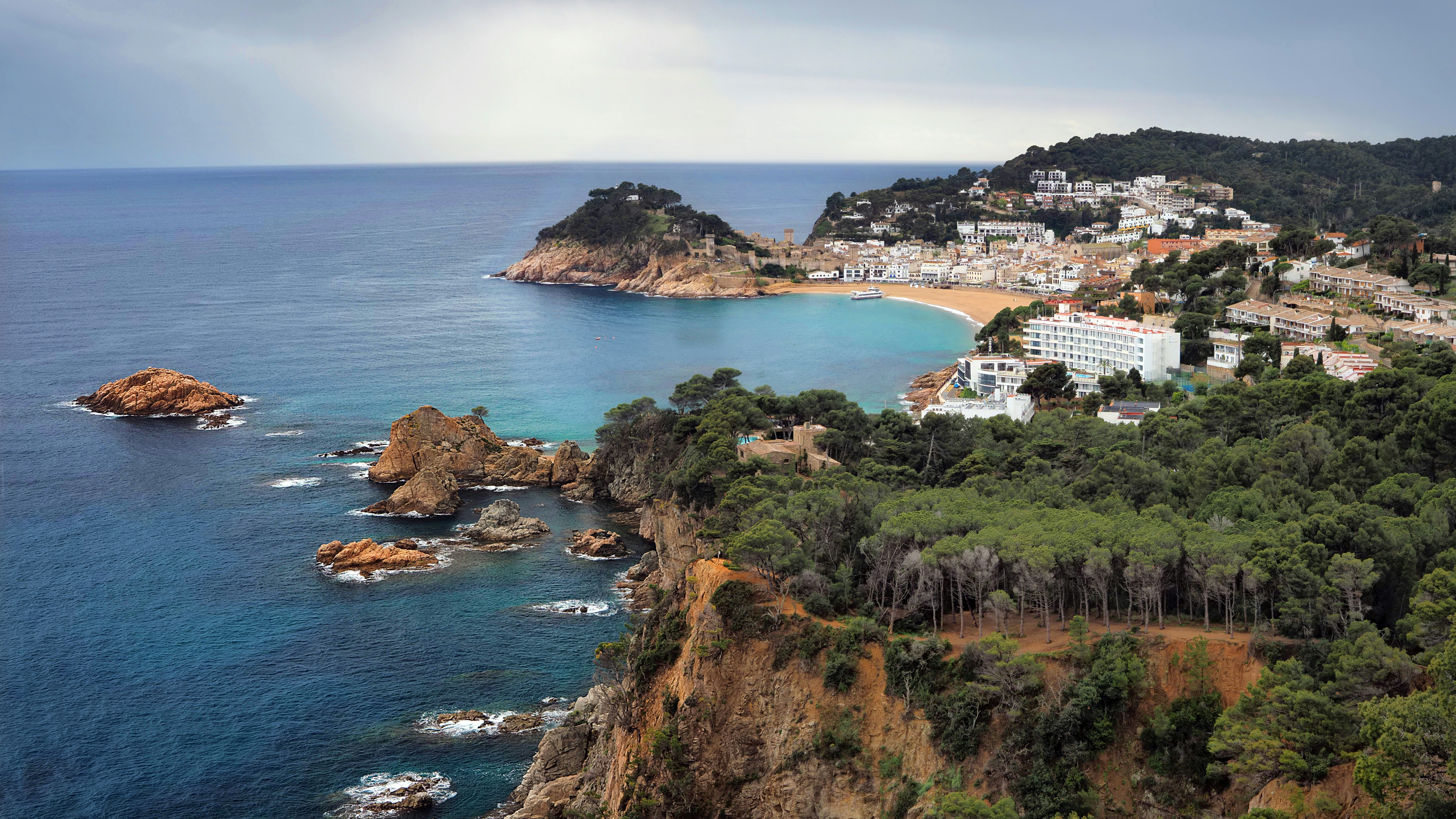 Coastal town bordered by rugged cliffs and vibrant blue waters.