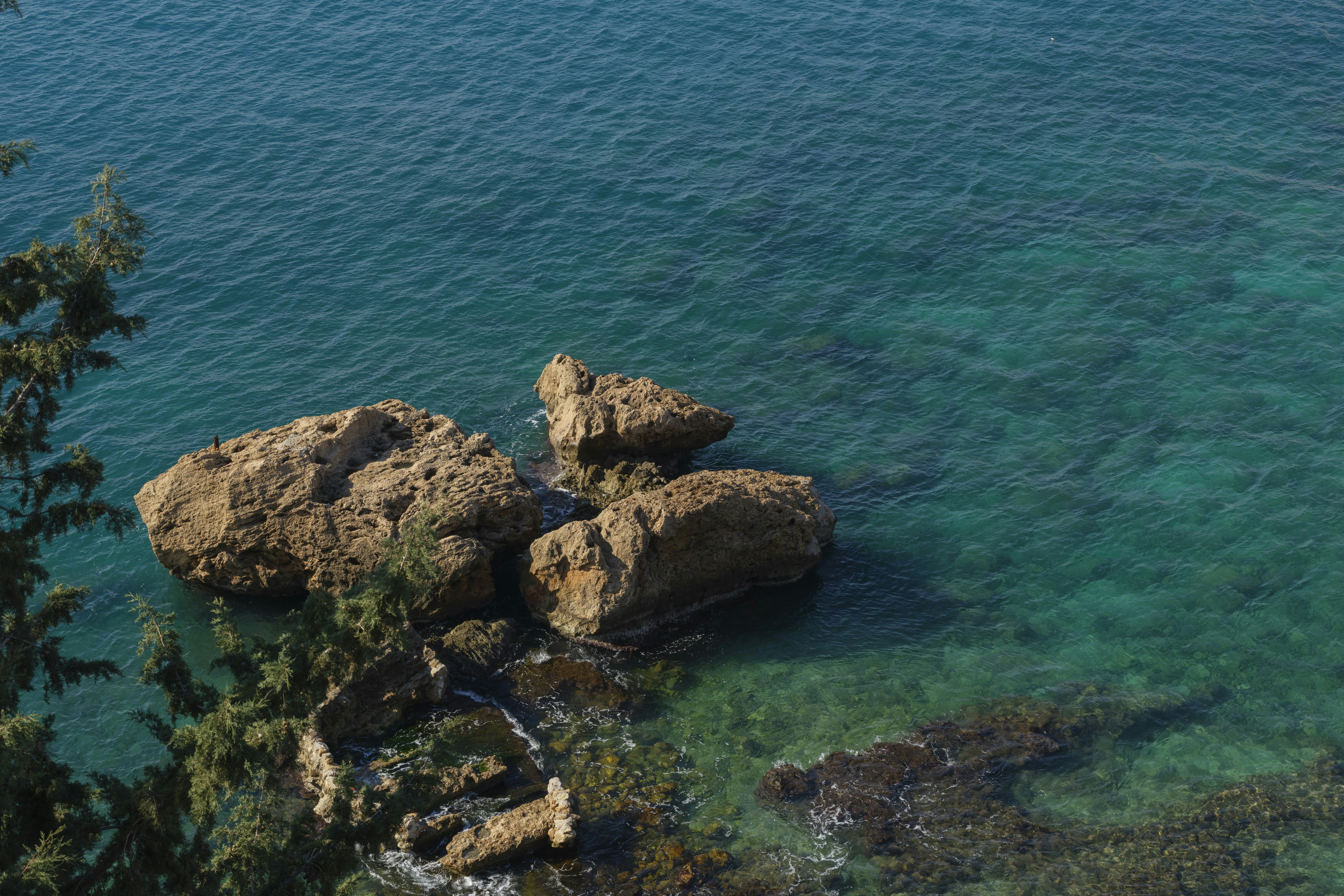 Rocks jut out into the clear blue sea. photo – Free Background Image on ...