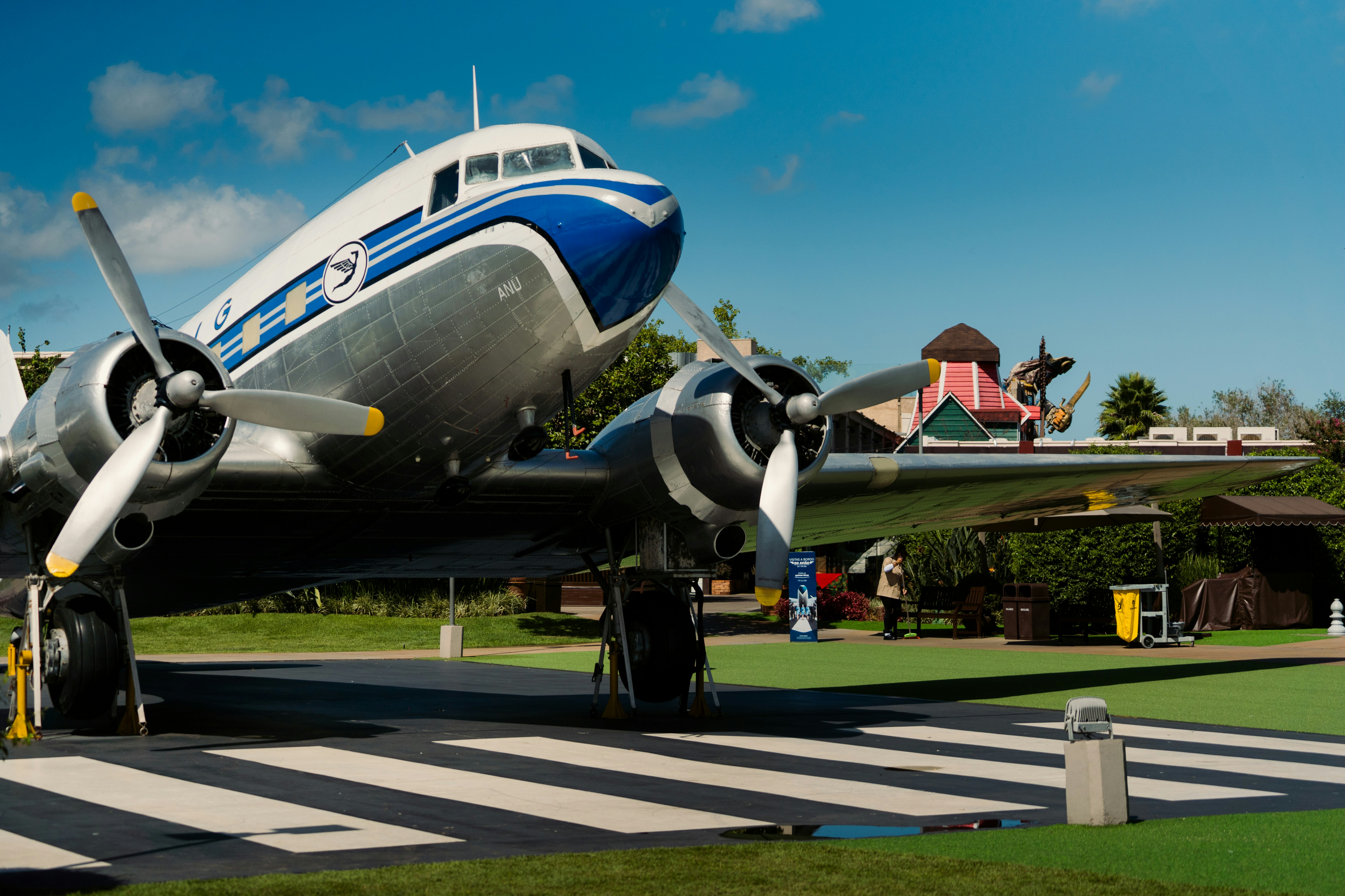 Vintage airplane with a blue and white livery rests on a striped runway under a clear sky.