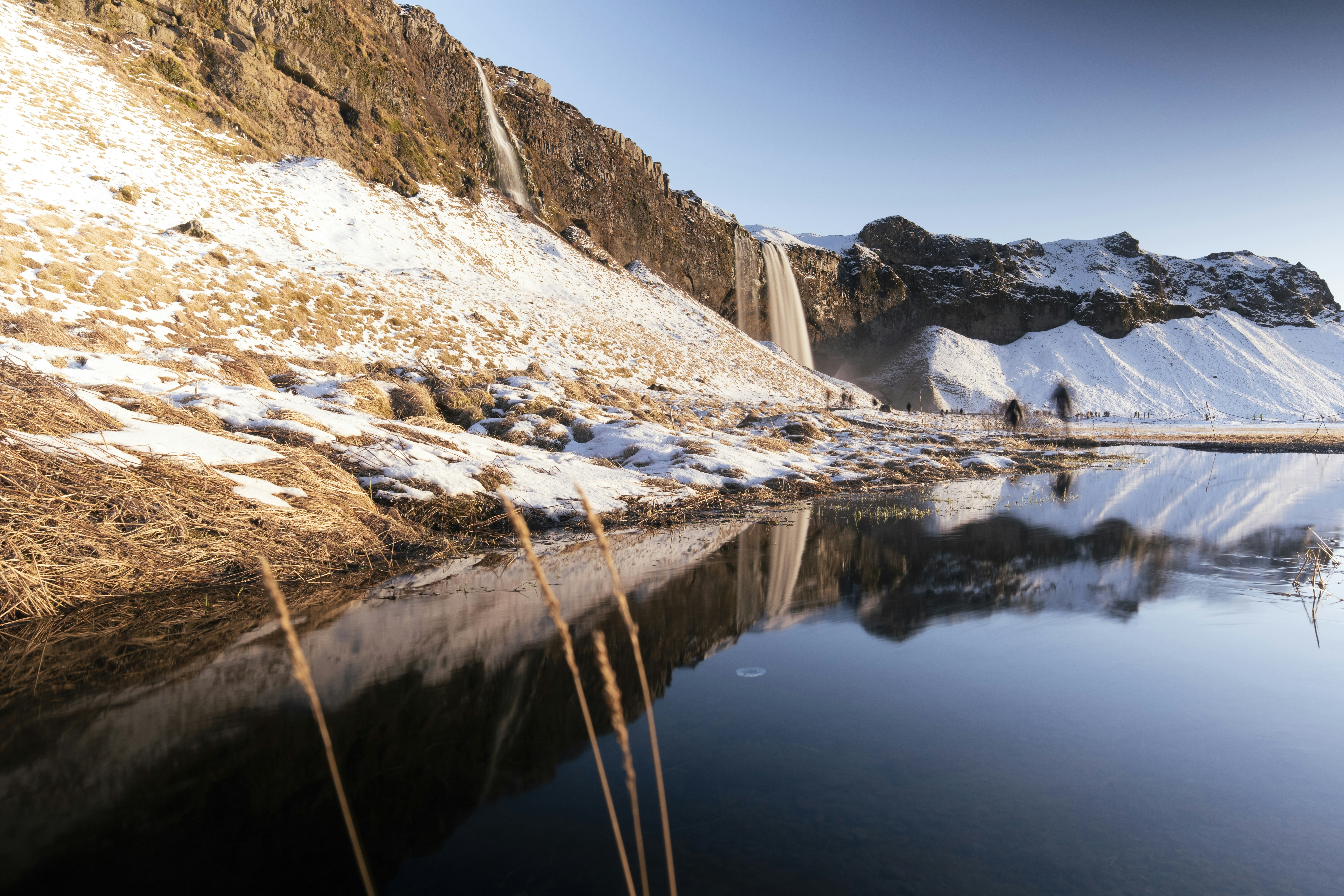 Cascade at Snowline Over a Mirror-Lake Fjord