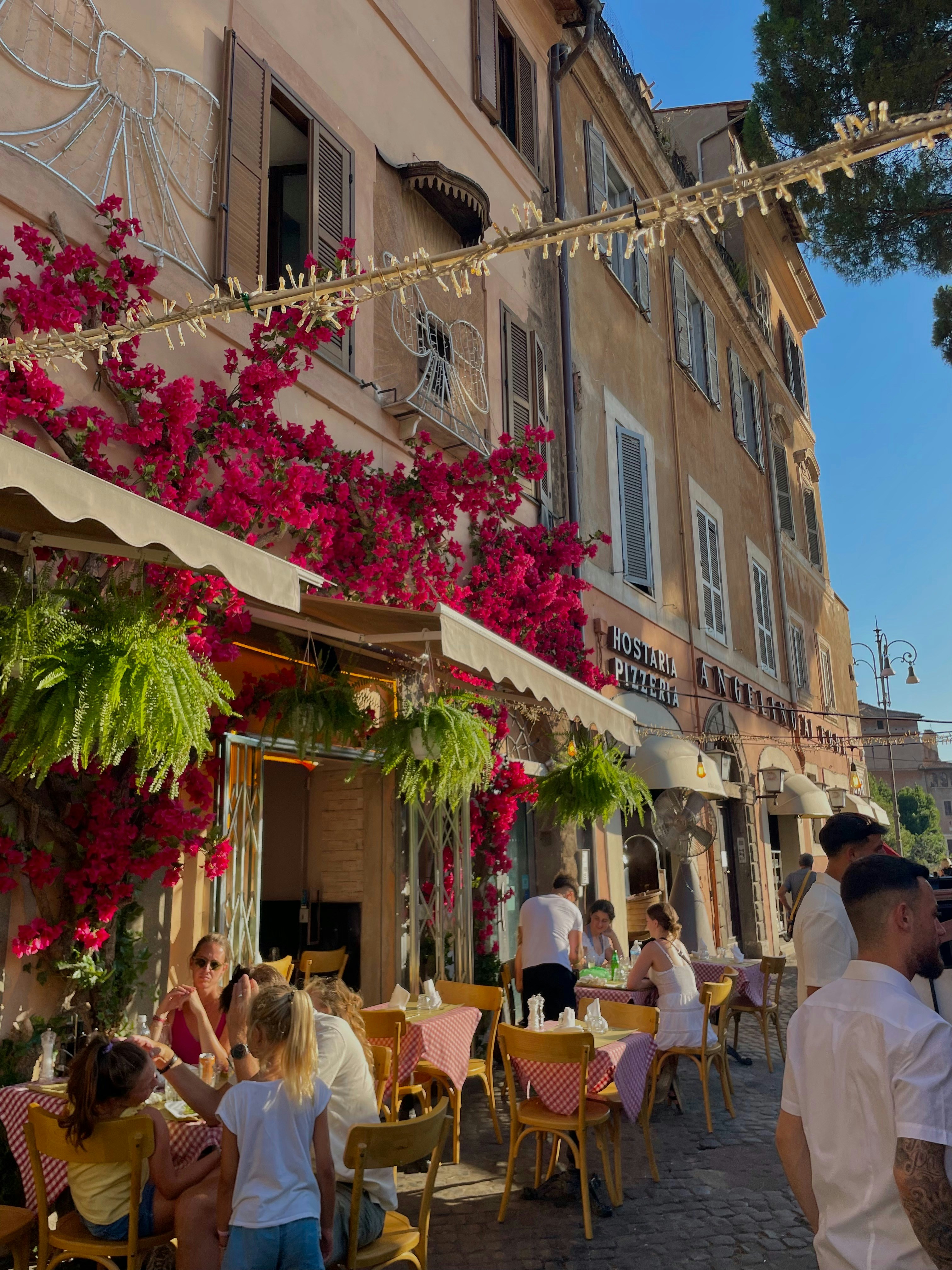 A restaurant with tables, people, and bright flowers.