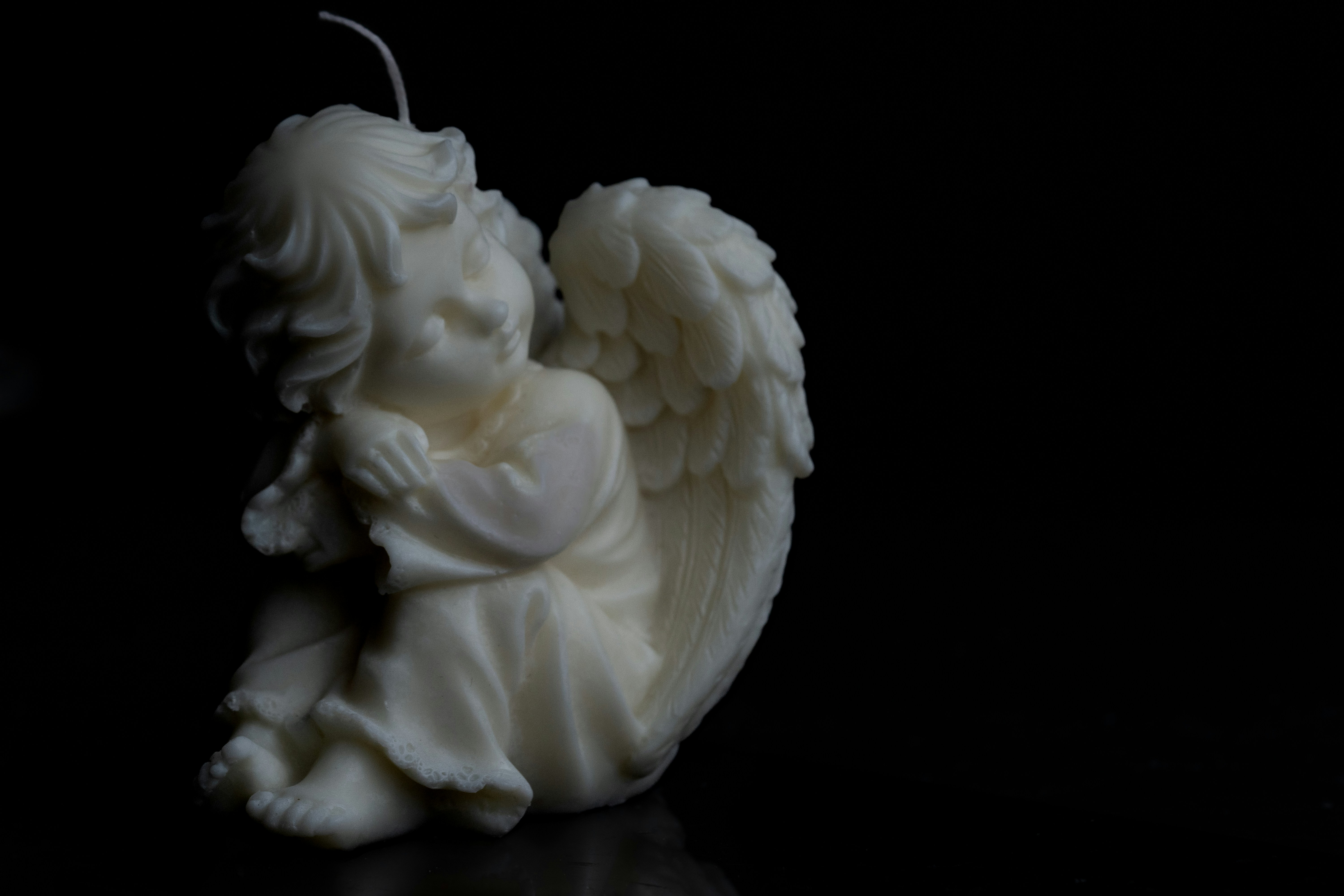 Whisper of Light: A White Angel Candle in Shadow