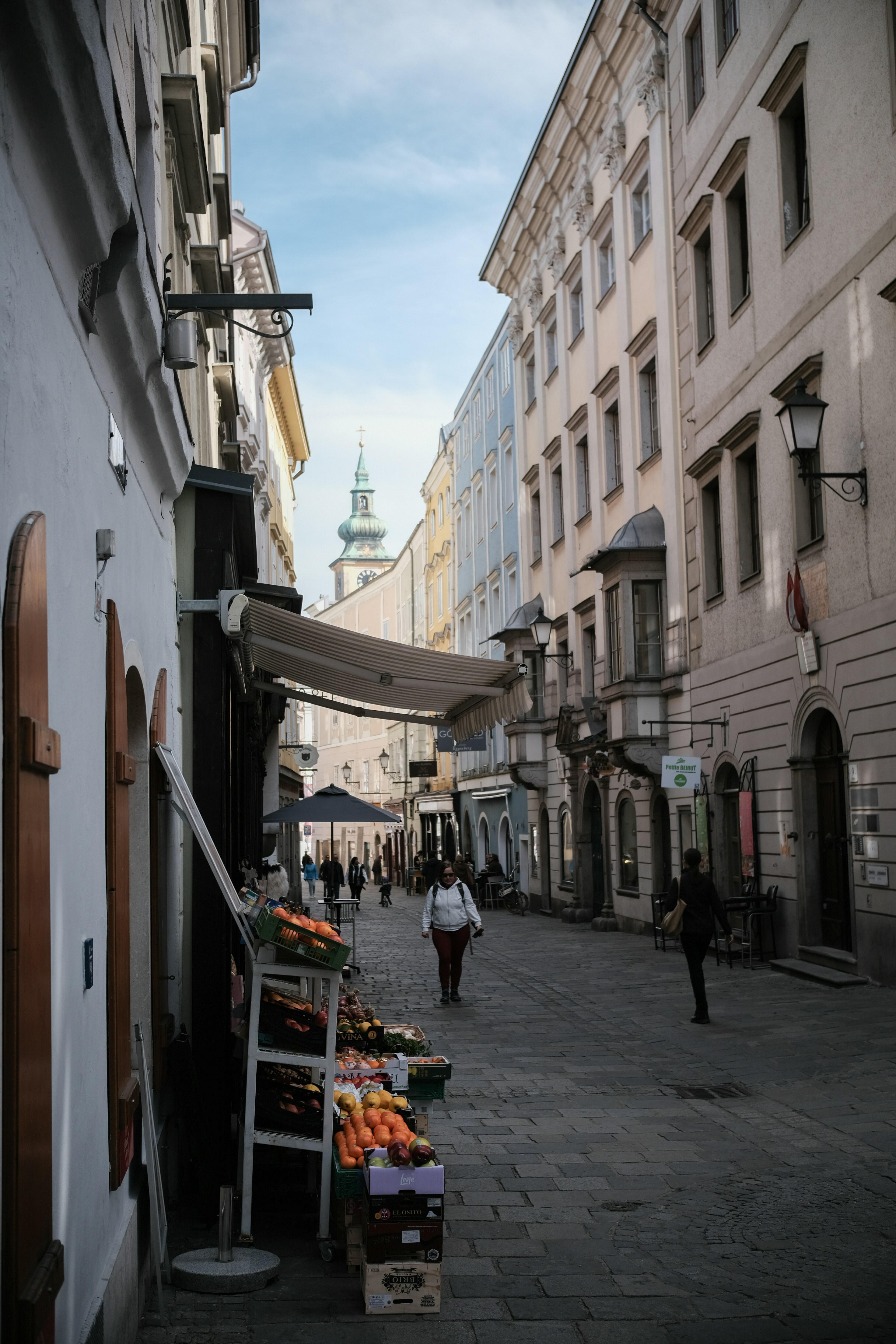 Cobbled Corridor: Market Stalls Framing a Distant Spire