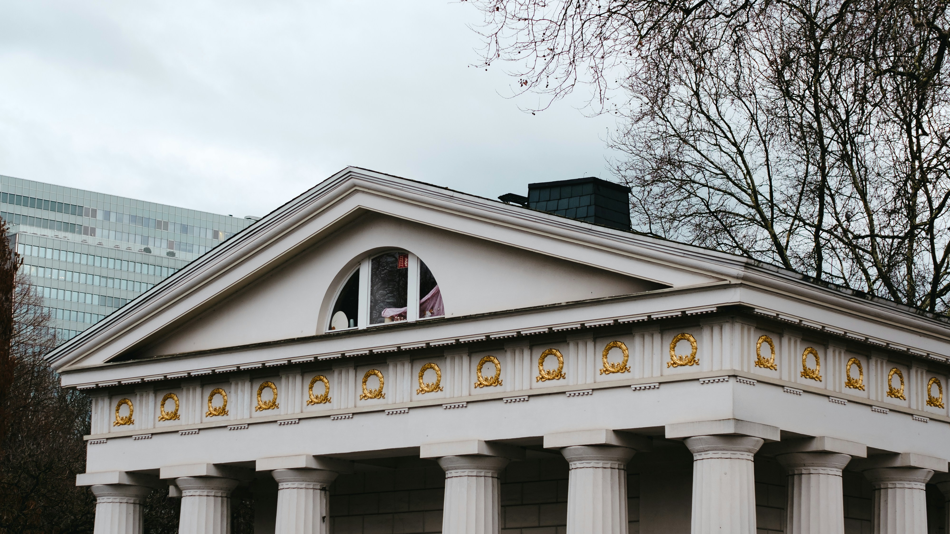 A classical building stands with a modern skyscraper behind it. photo ...