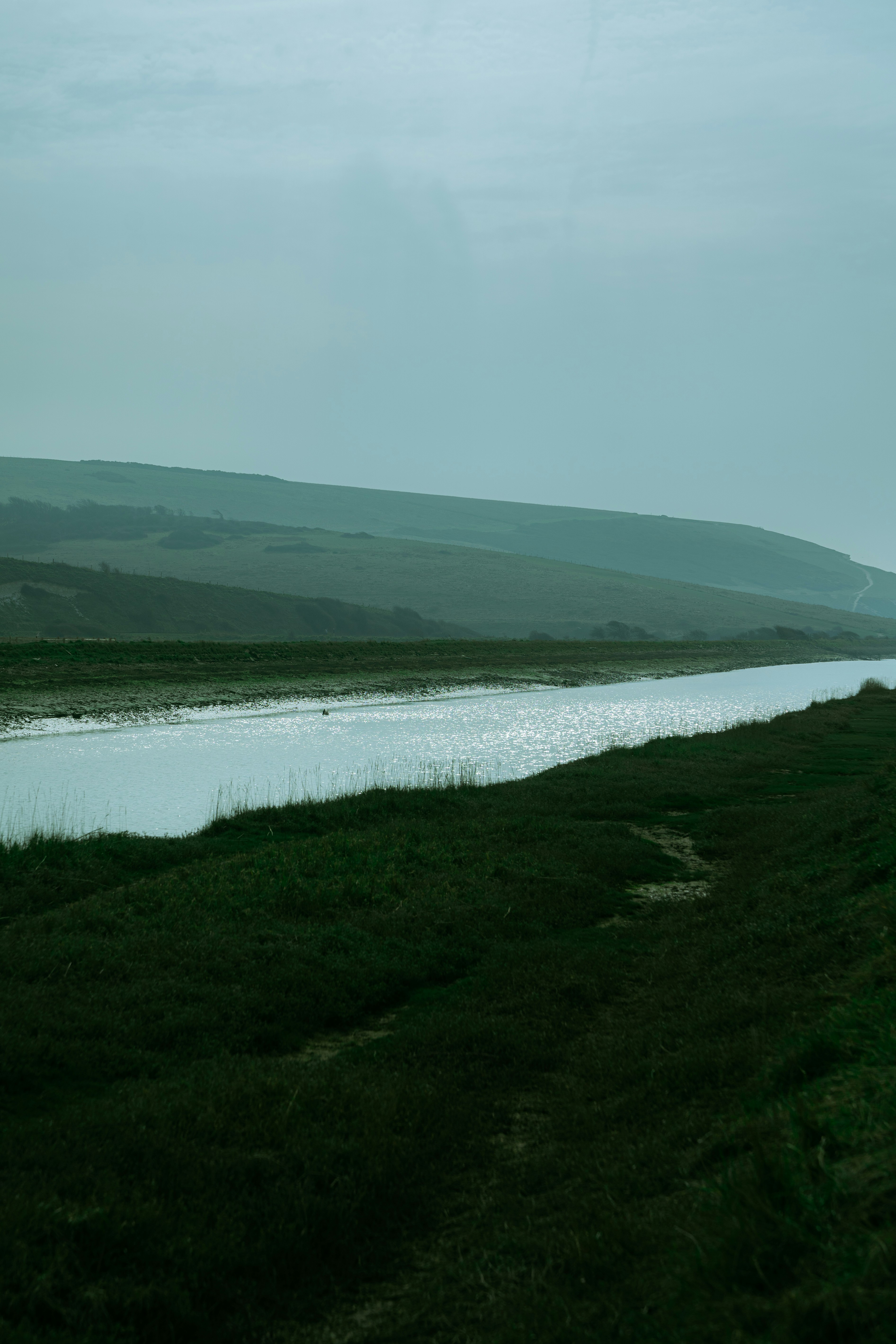 Teal Quiet: A Narrow Waterway Framing Rolling Hills