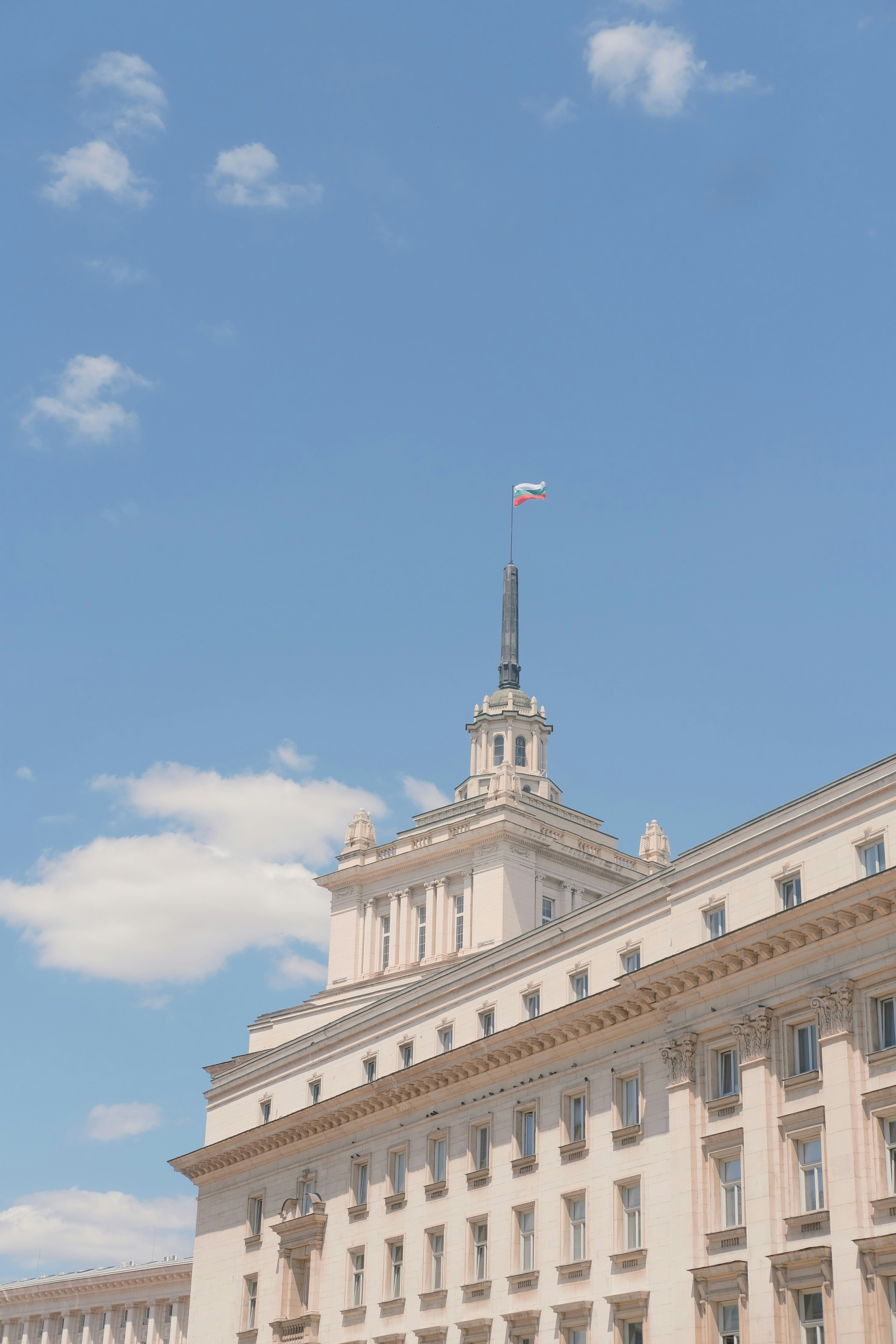 Historic government building with a prominent spire against a clear blue sky.