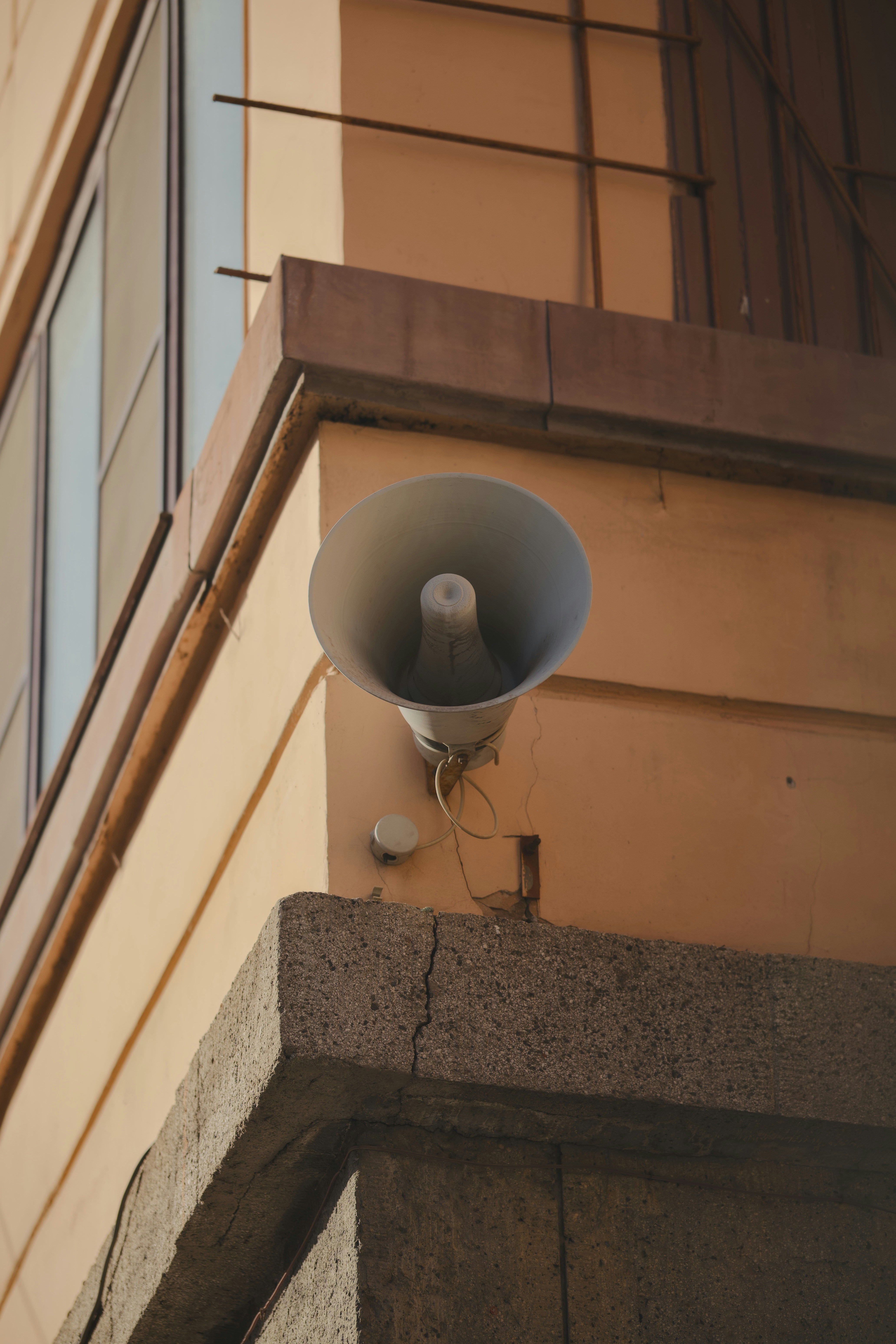 Concrete Echo: A Sunlit Megaphone Anchored to a City Facade
