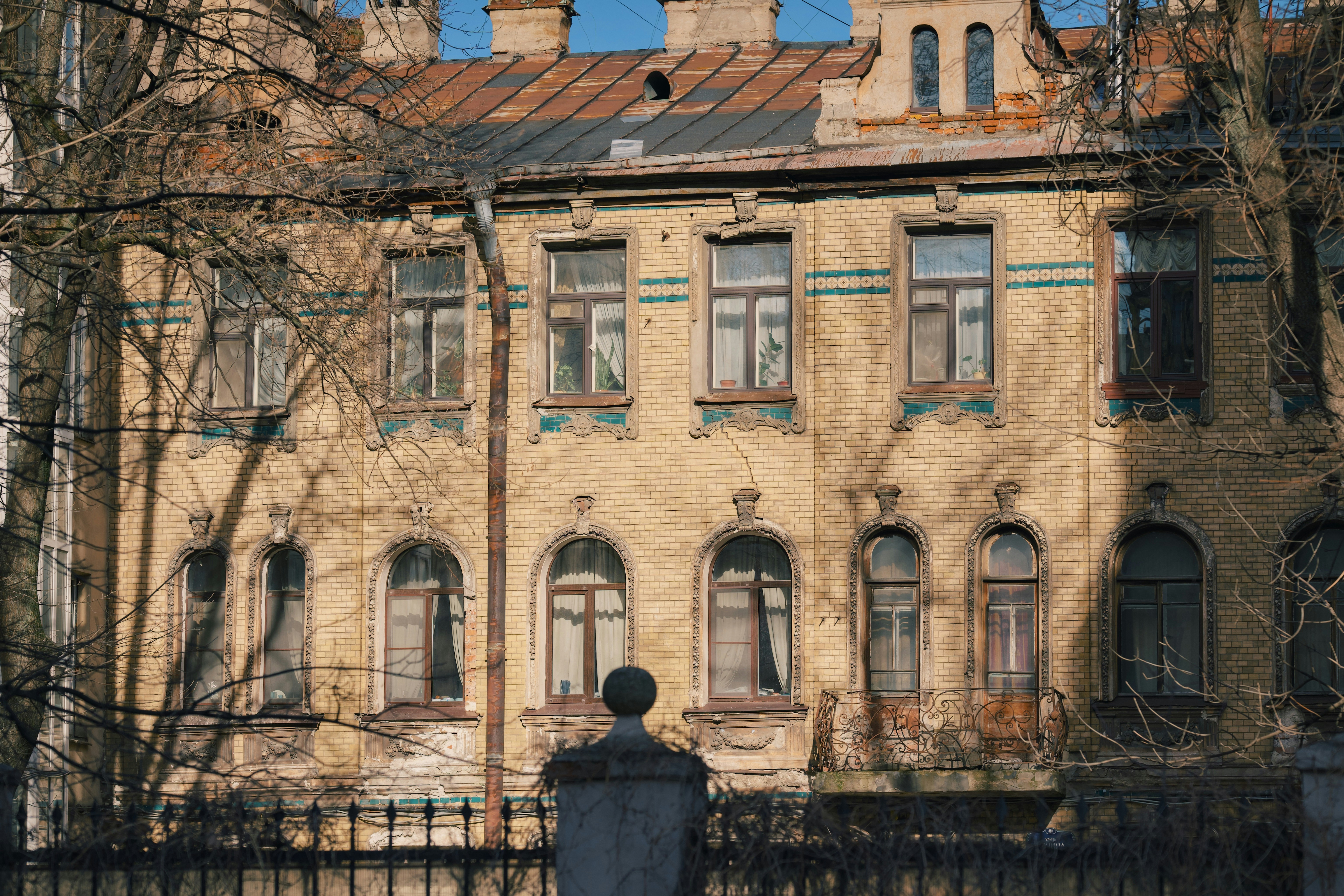 Weathered facade of an old building with ornate windows and shadowed brickwork.