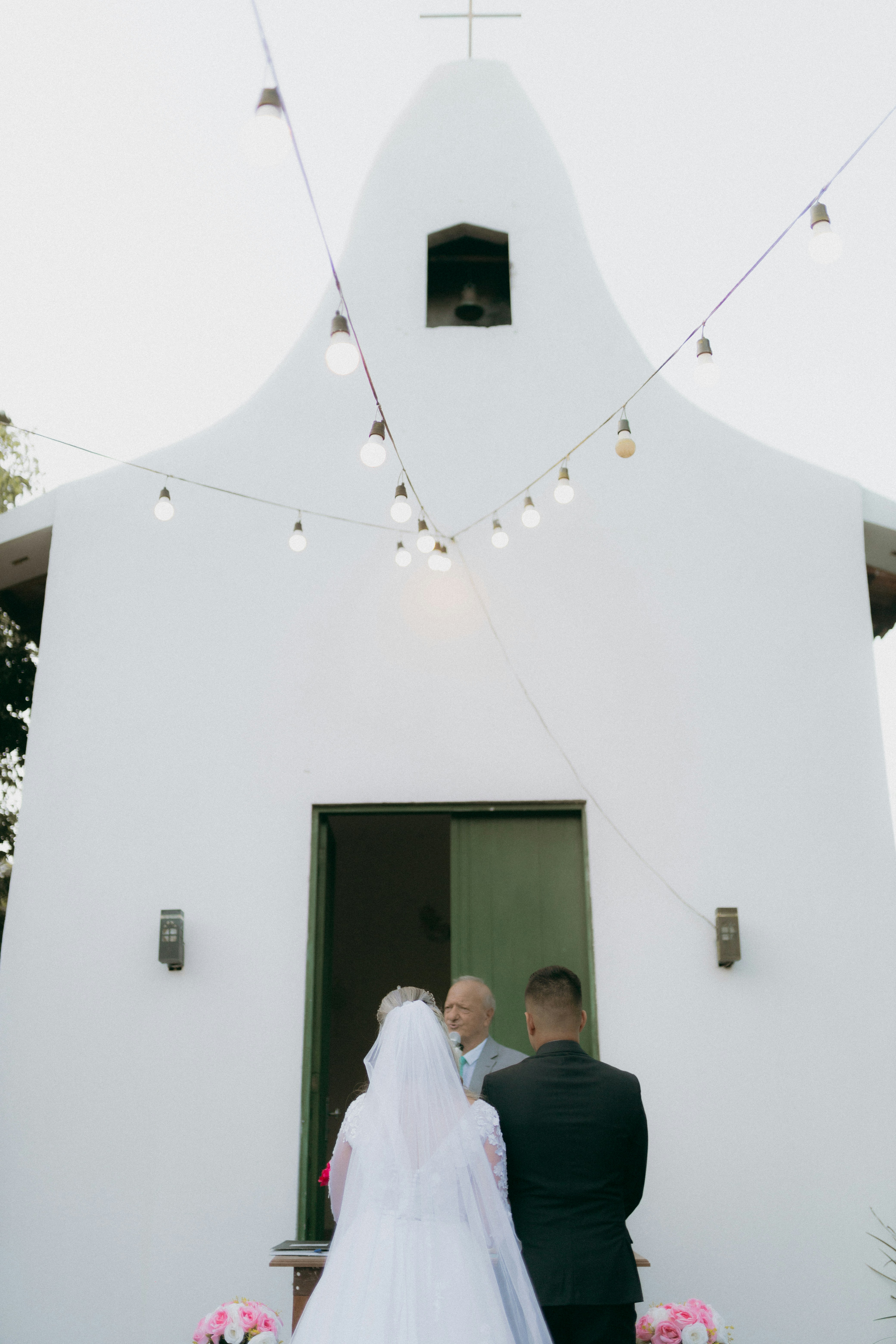 Vows Under Warm Bulbs at a White-Washed Chapel