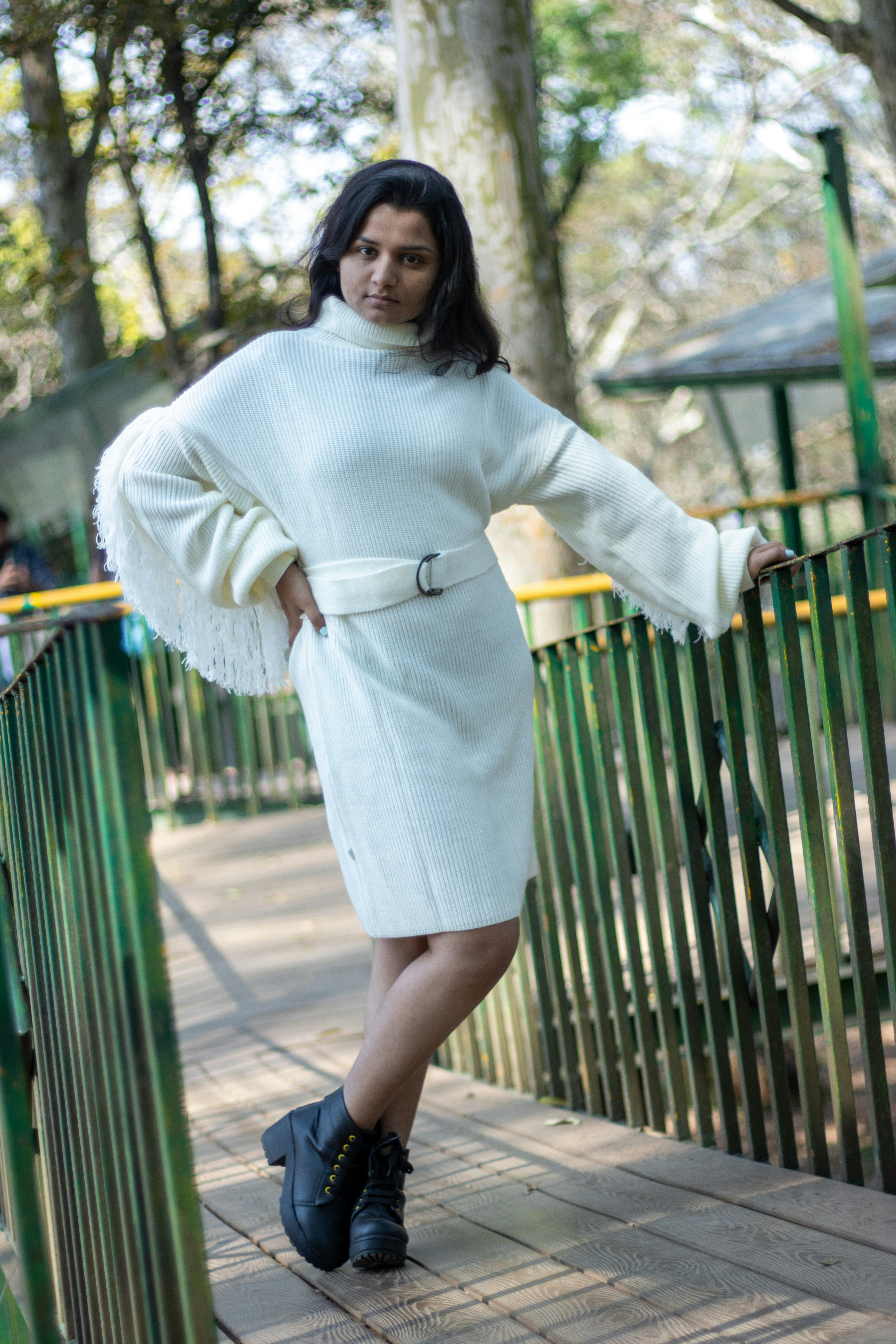 White knit dress on a sunlit bridge: confident pose in a park