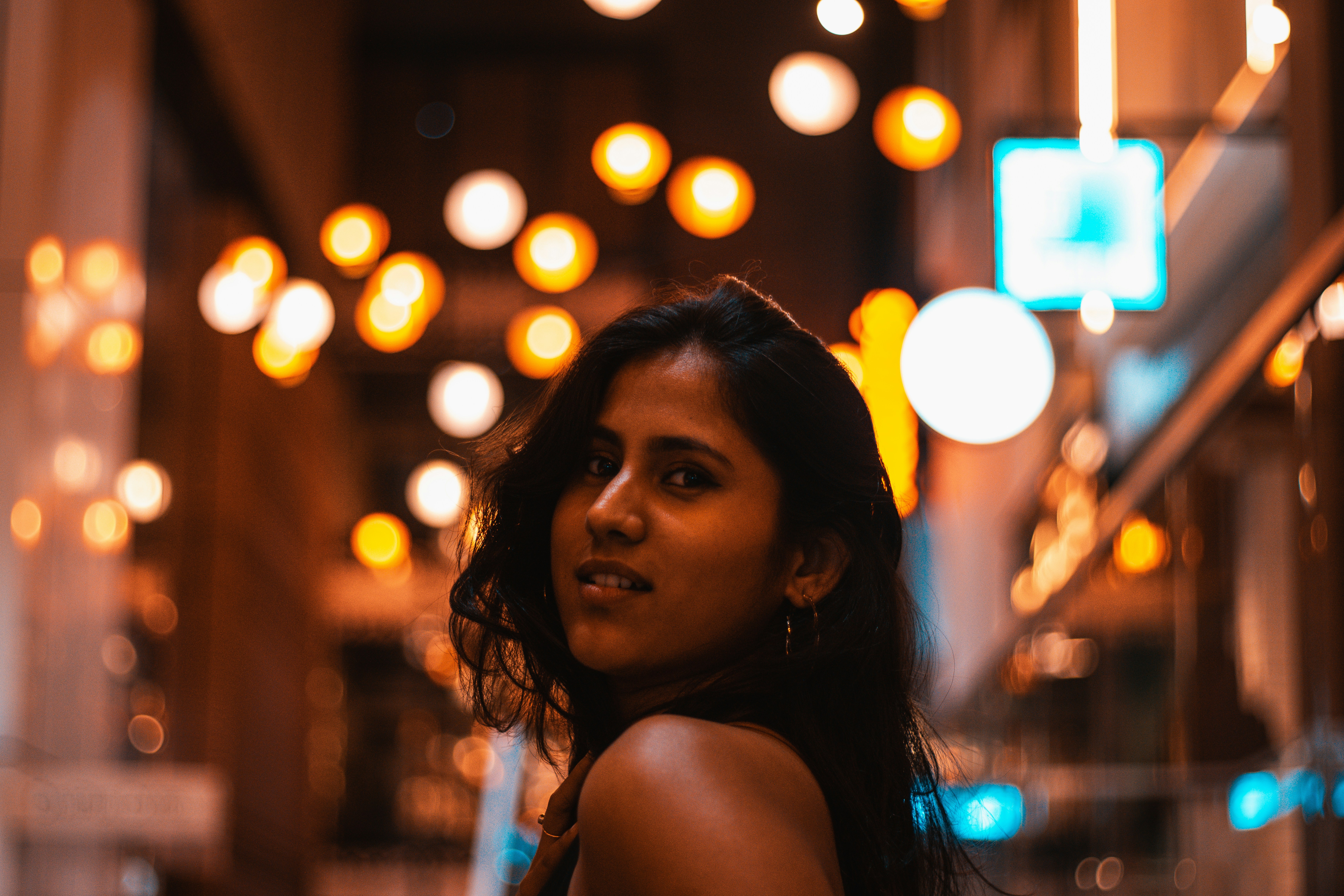 La femme sourit à la caméra avec des lumières en arrière-plan. photo ...