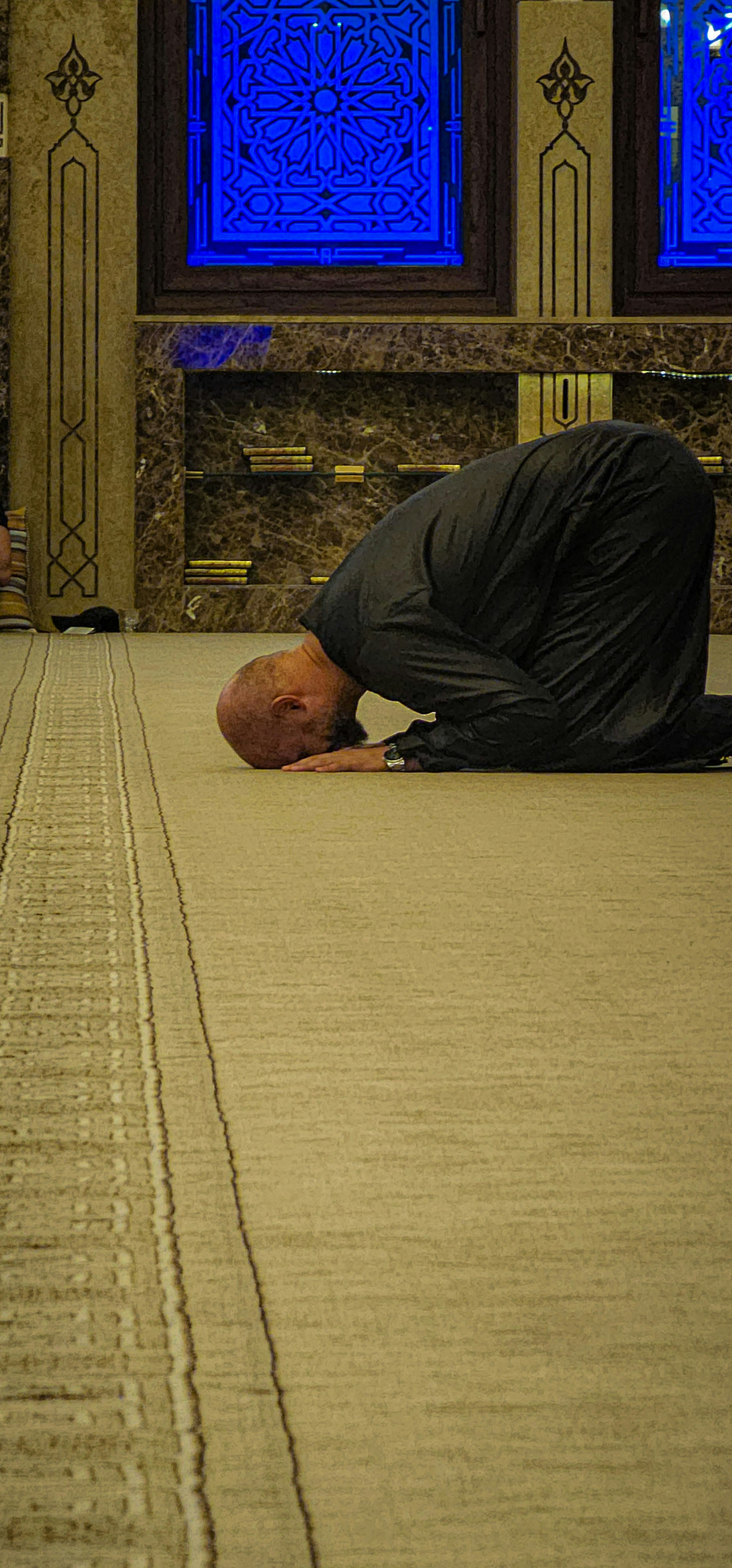 Prostration Beneath Azure Carved Panels in a Marble Prayer Hall