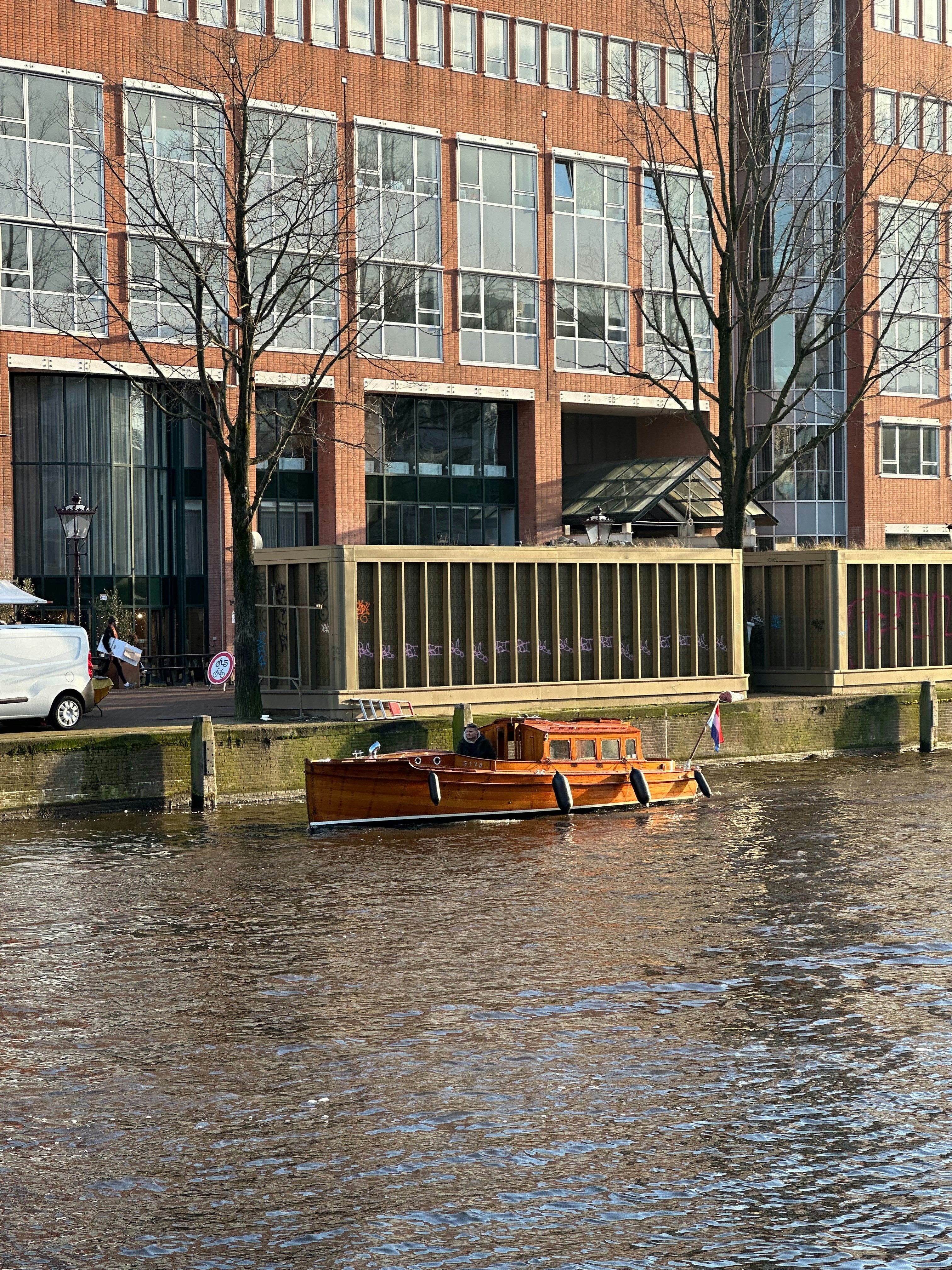 Timber Boat by the Canal: Quiet Vessel Against an Urban Brickfront