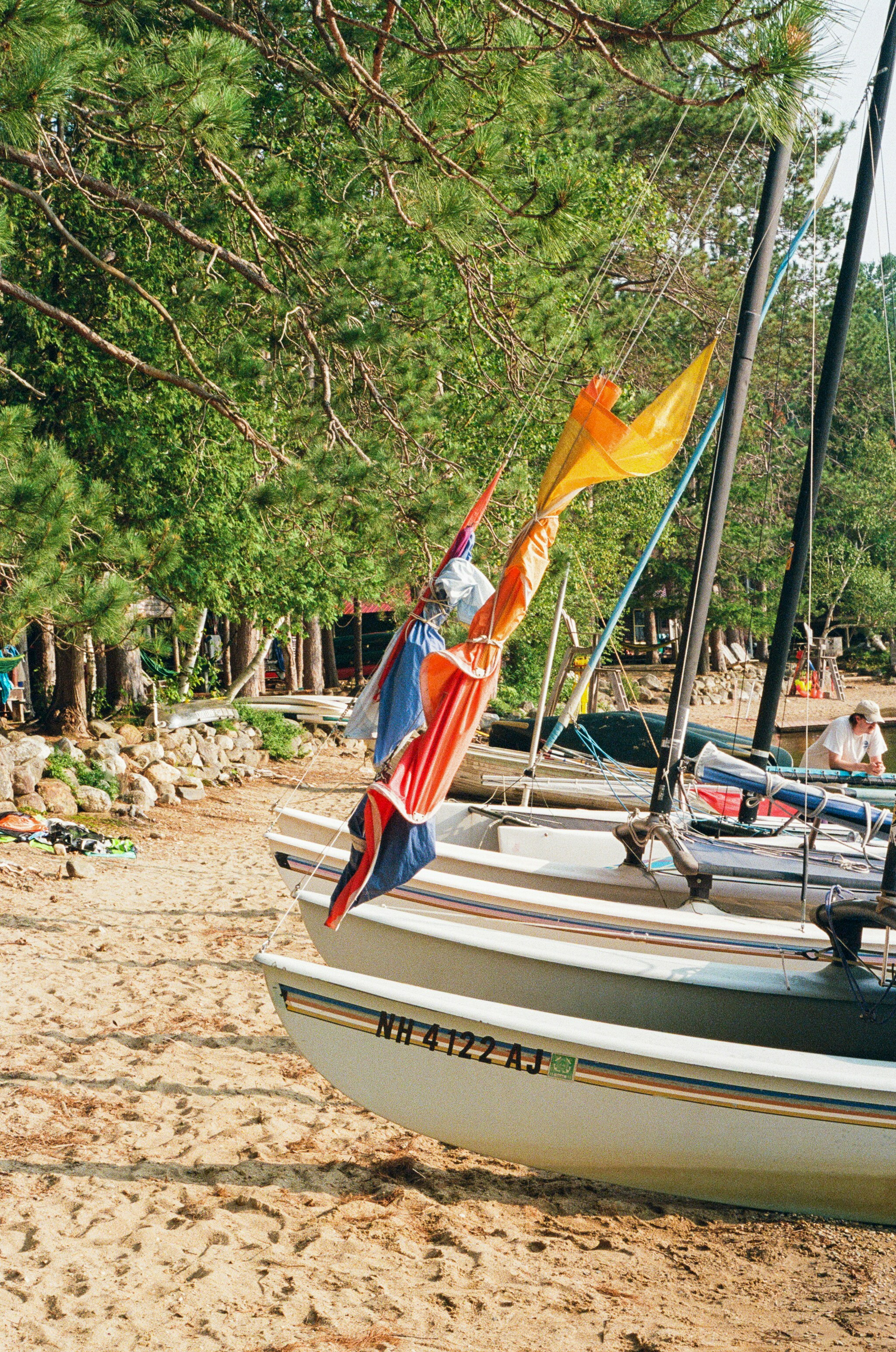 Colorful sail boats sit on the shore at a summer camp in Maine.