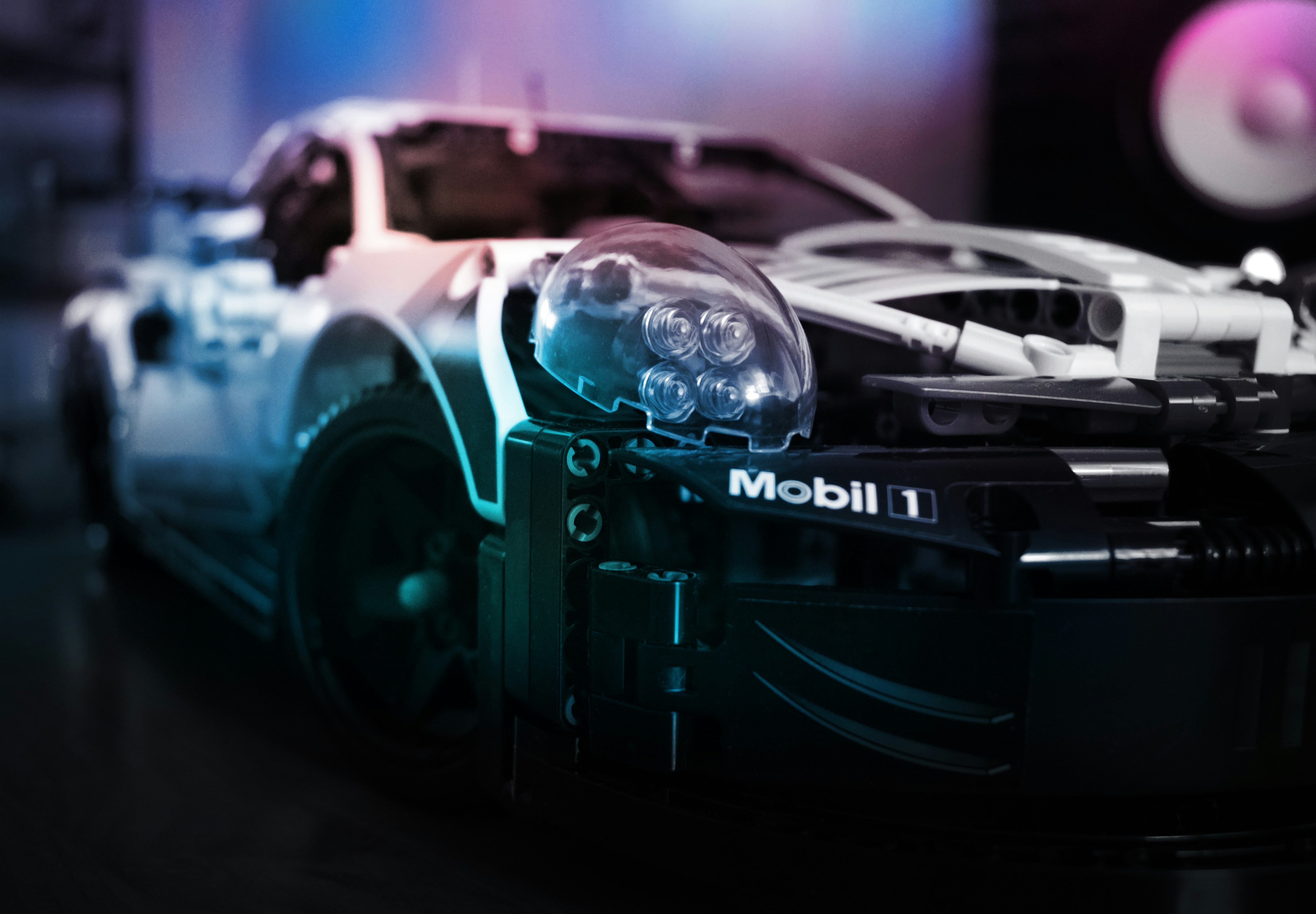 LEGO Porsche model illuminated by colorful neon lights, highlighting its sleek contours and intricate details.