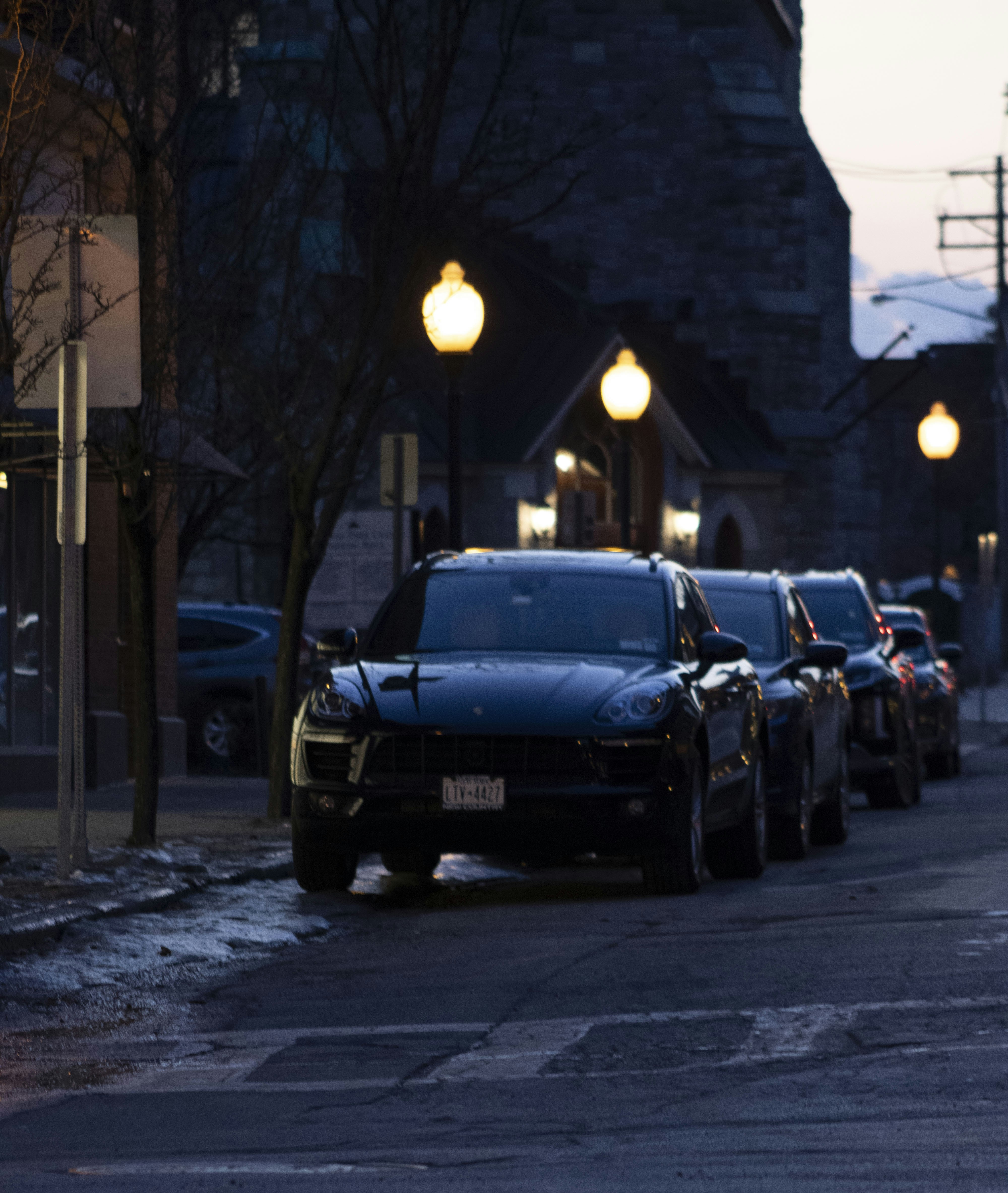 Blue Hour Row: Parked SUV silhouettes under warm streetlamps