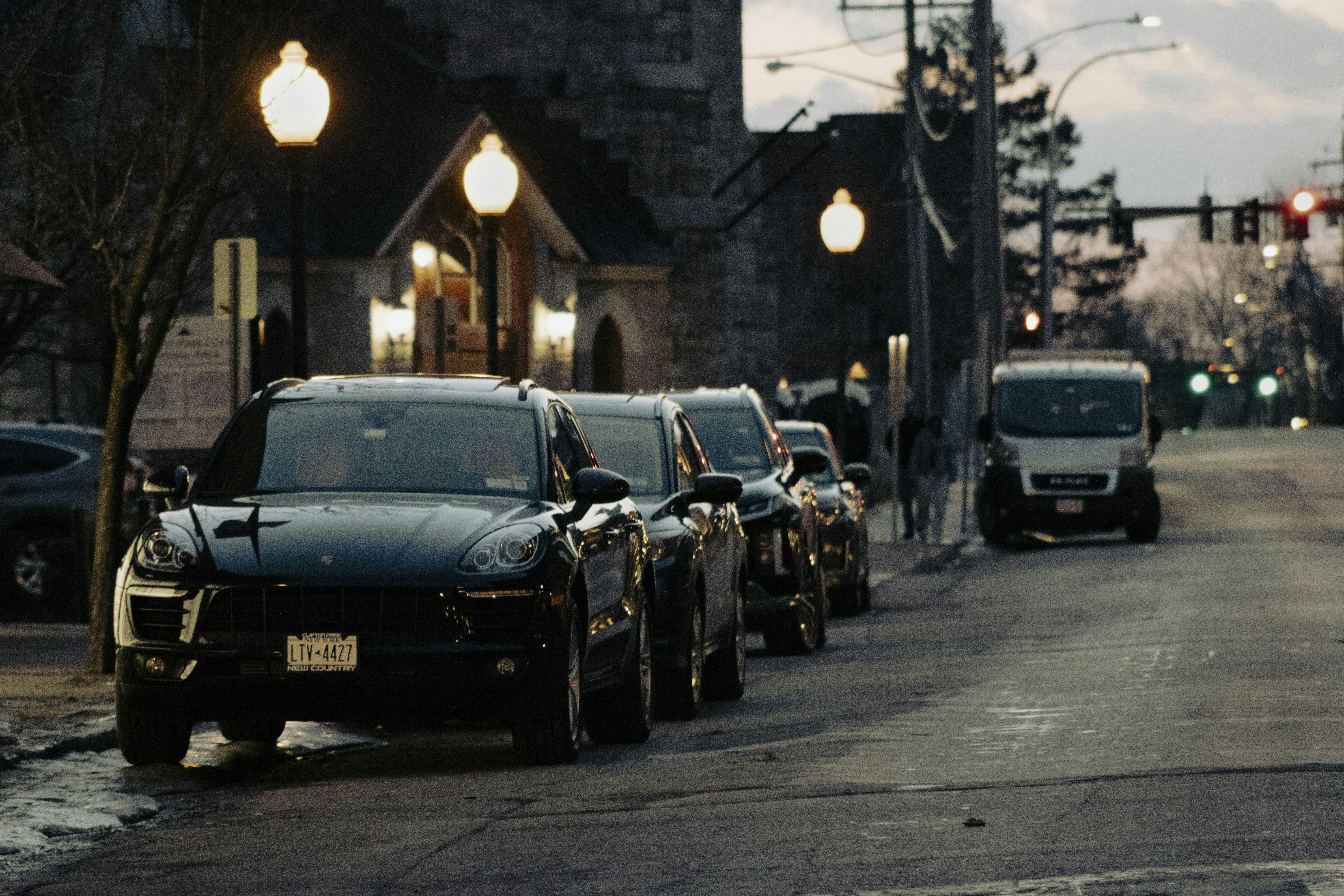 Evening Lineup: Parked Cars Beneath Warm Streetlamp Glow