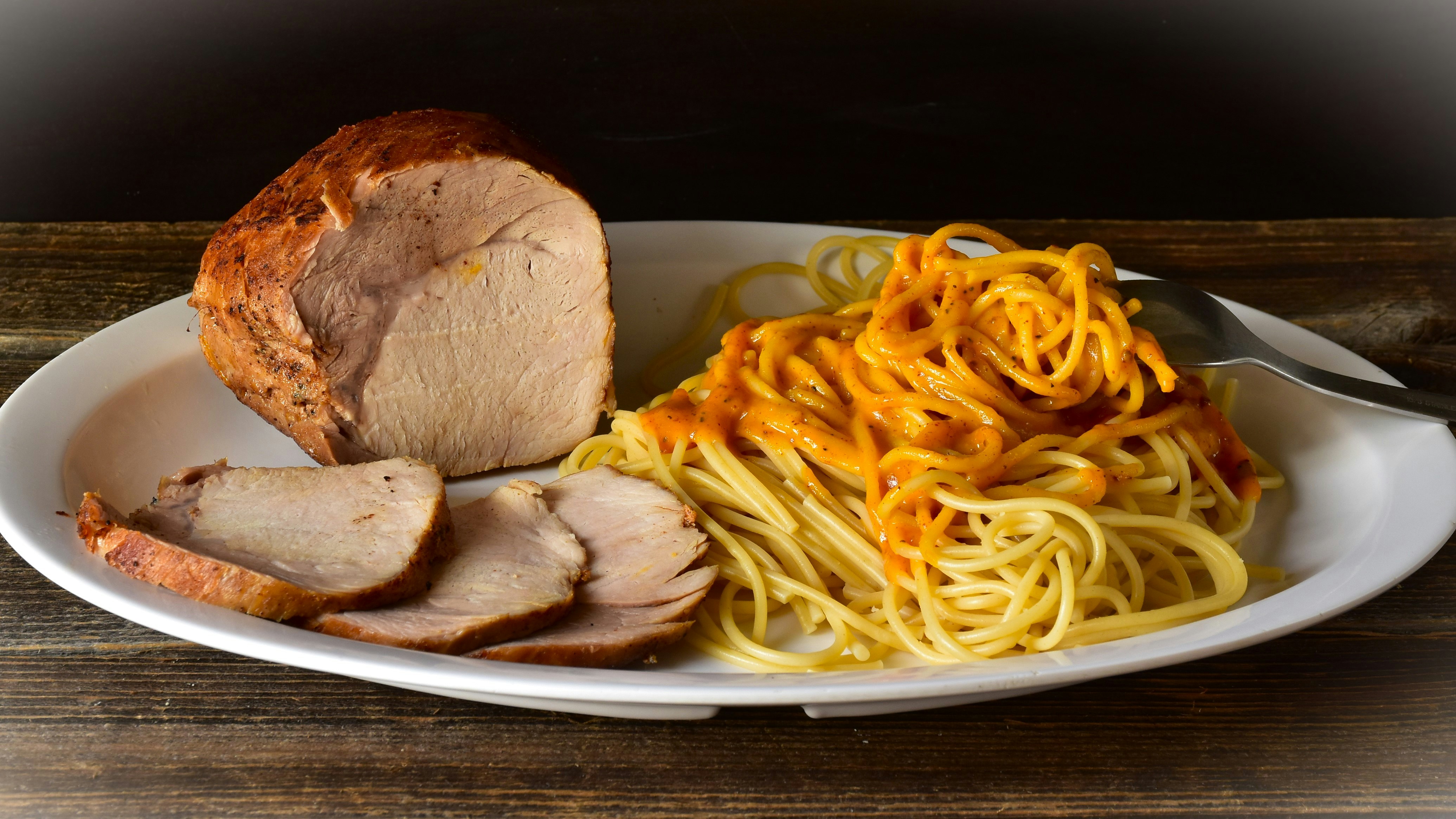 Sliced Tenderness: Herb-Crusted Roast with Twirling Pasta