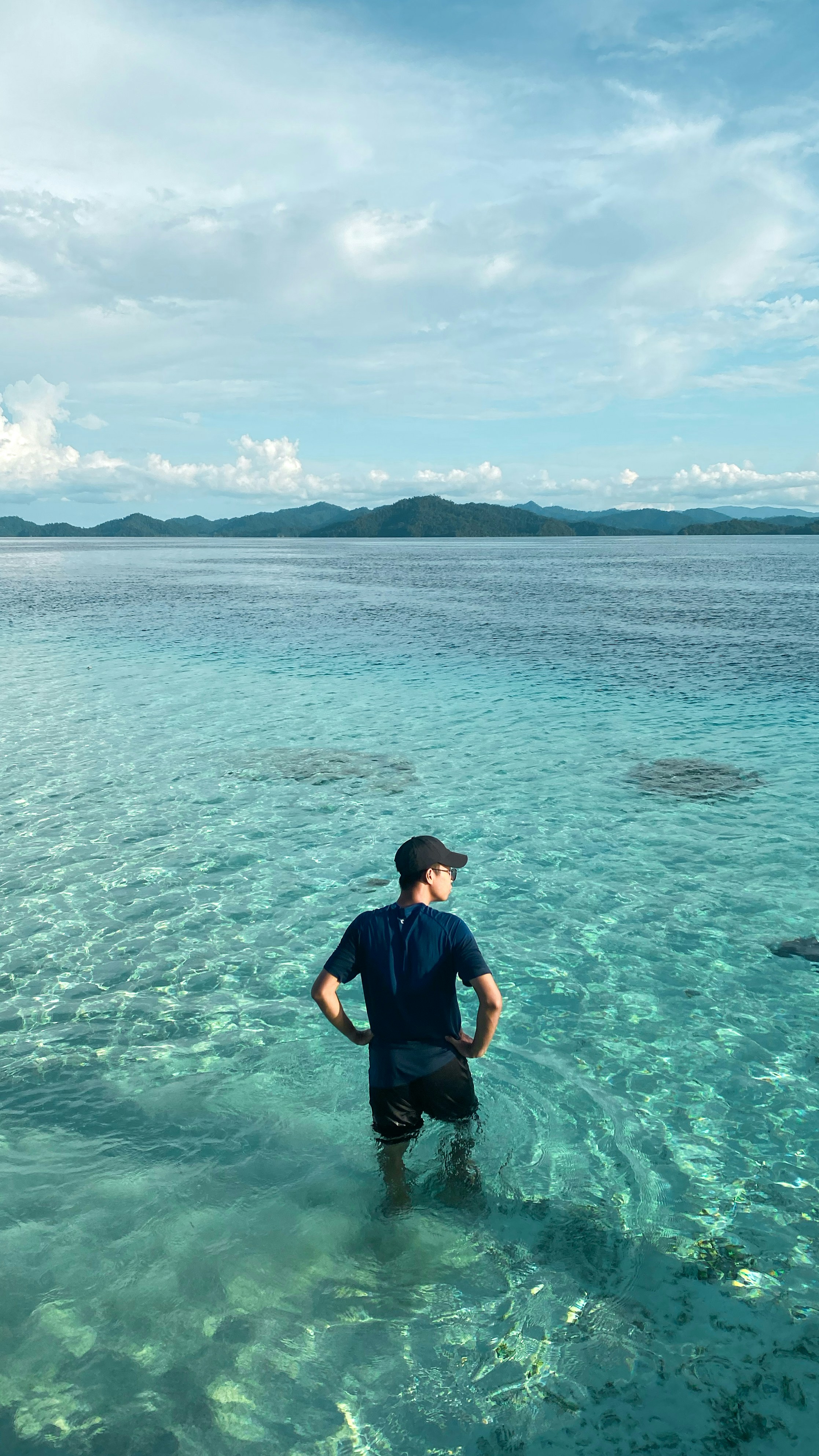 Man stands in clear water, gazing at the ocean. photo – Free Background ...