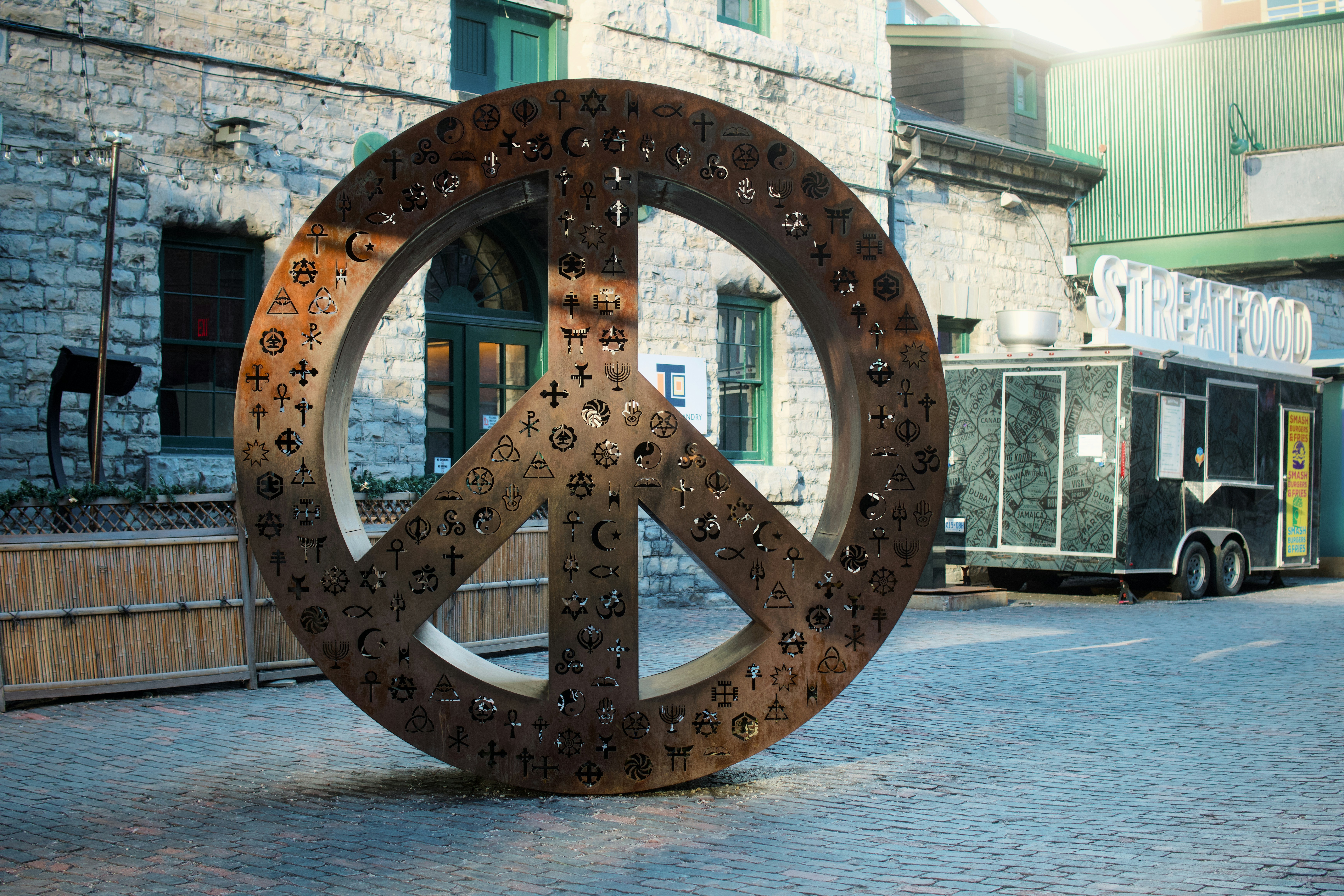 A rusty peace sign stands outdoors. photo – Free City Image on Unsplash