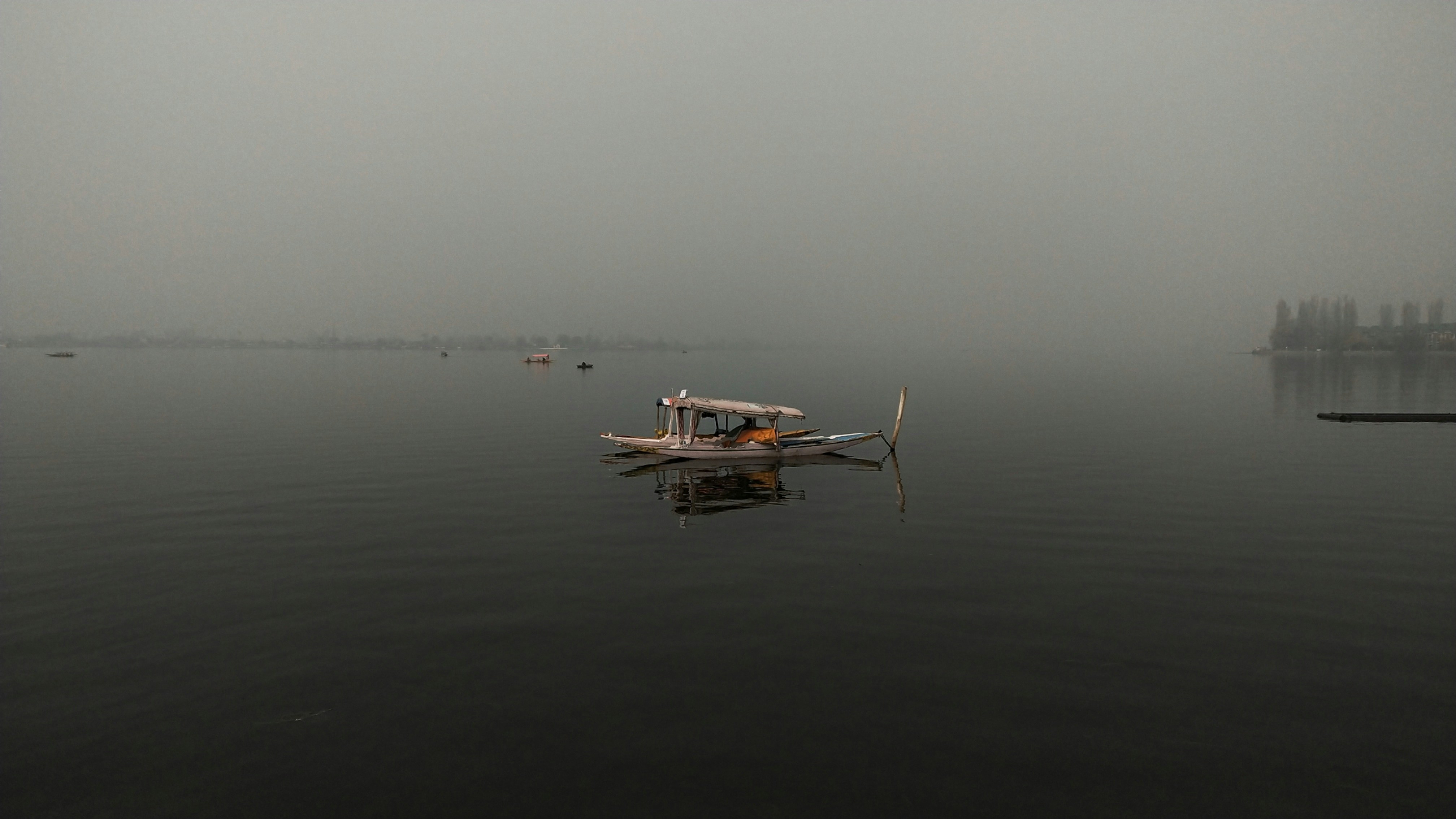 A boat sits on foggy, dark water.